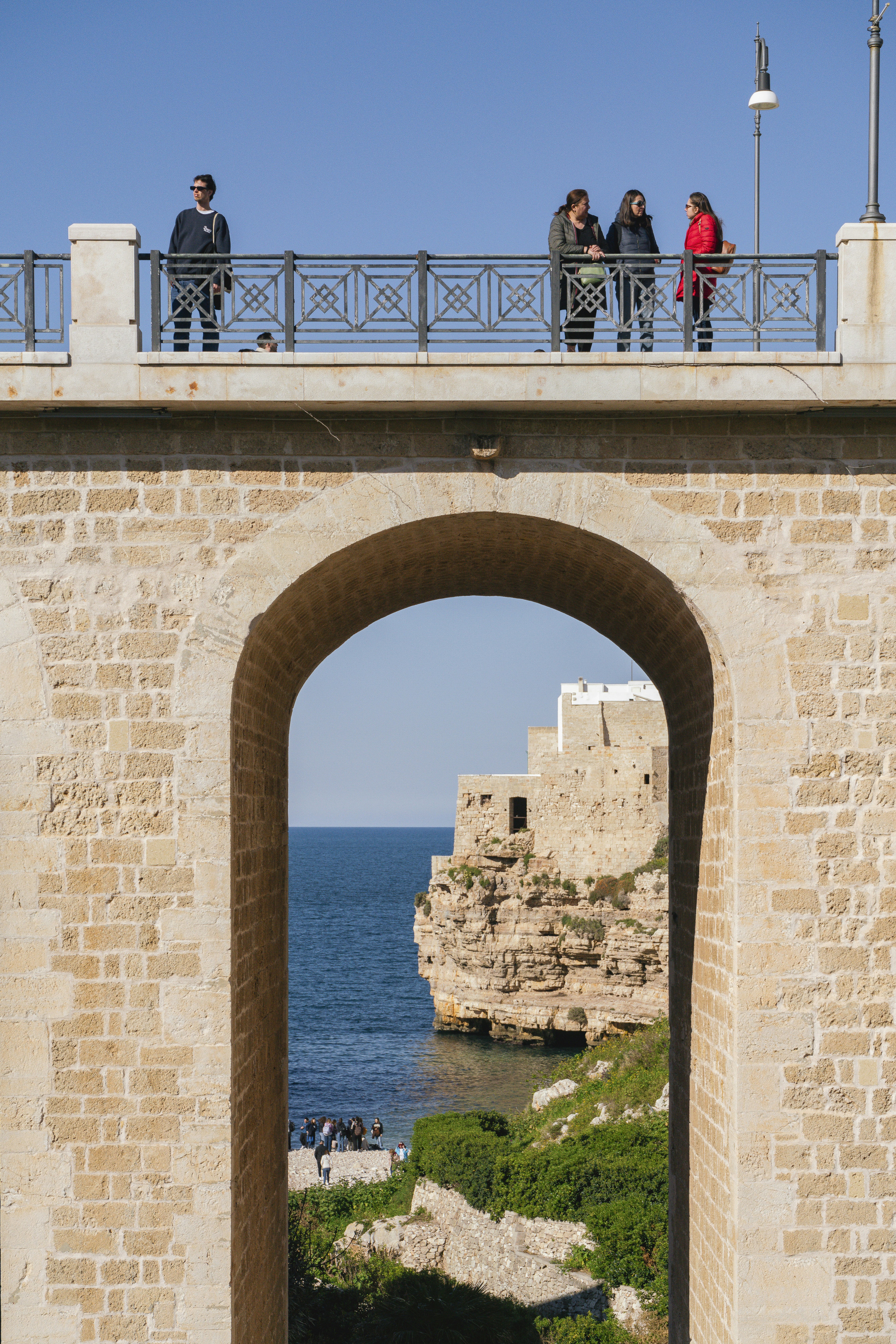 People stand on a bridge, overlooking the sea. photo – Free Human Image ...