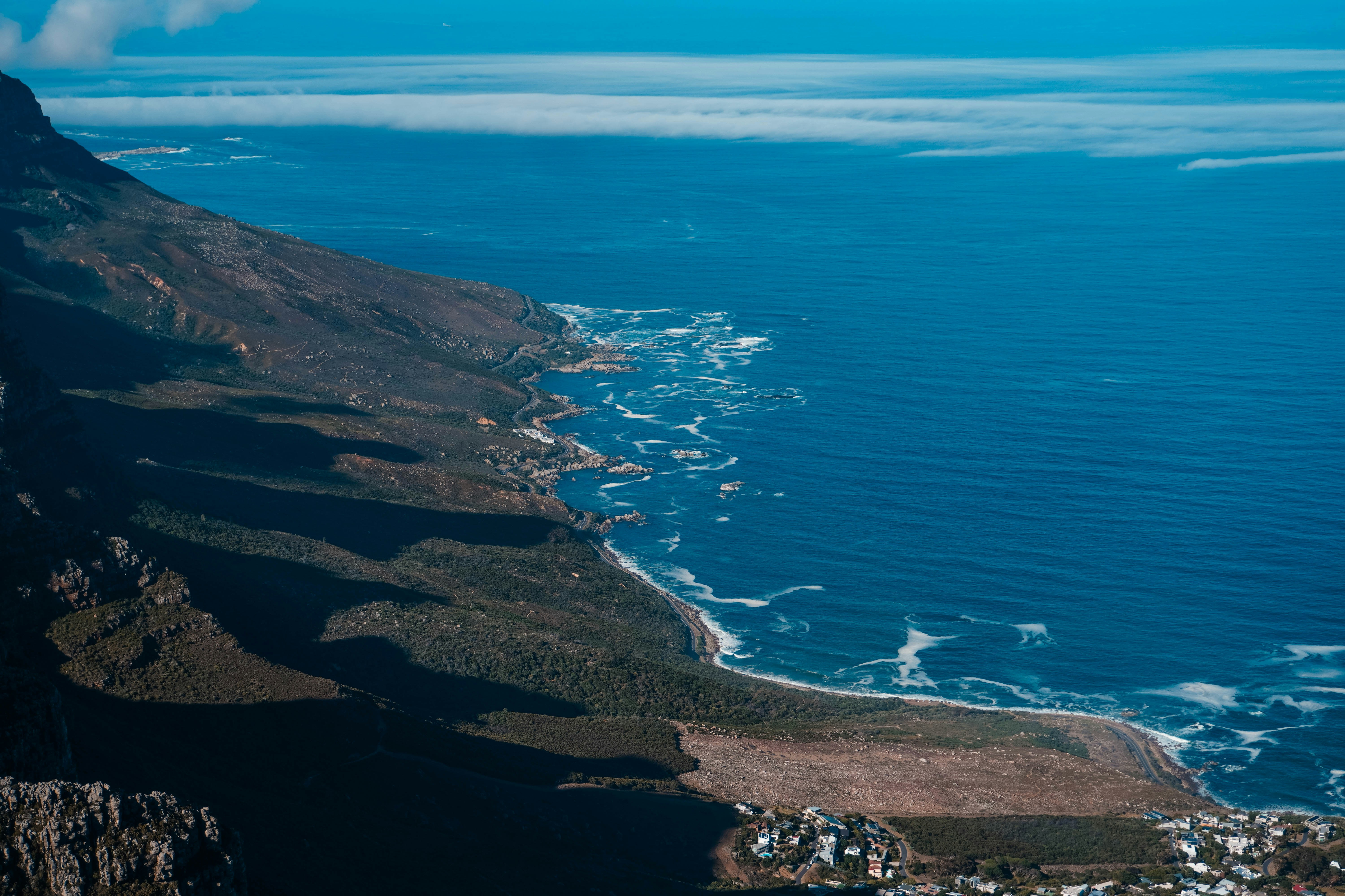 Expansive coastal view with rugged cliffs casting shadows over the ocean.