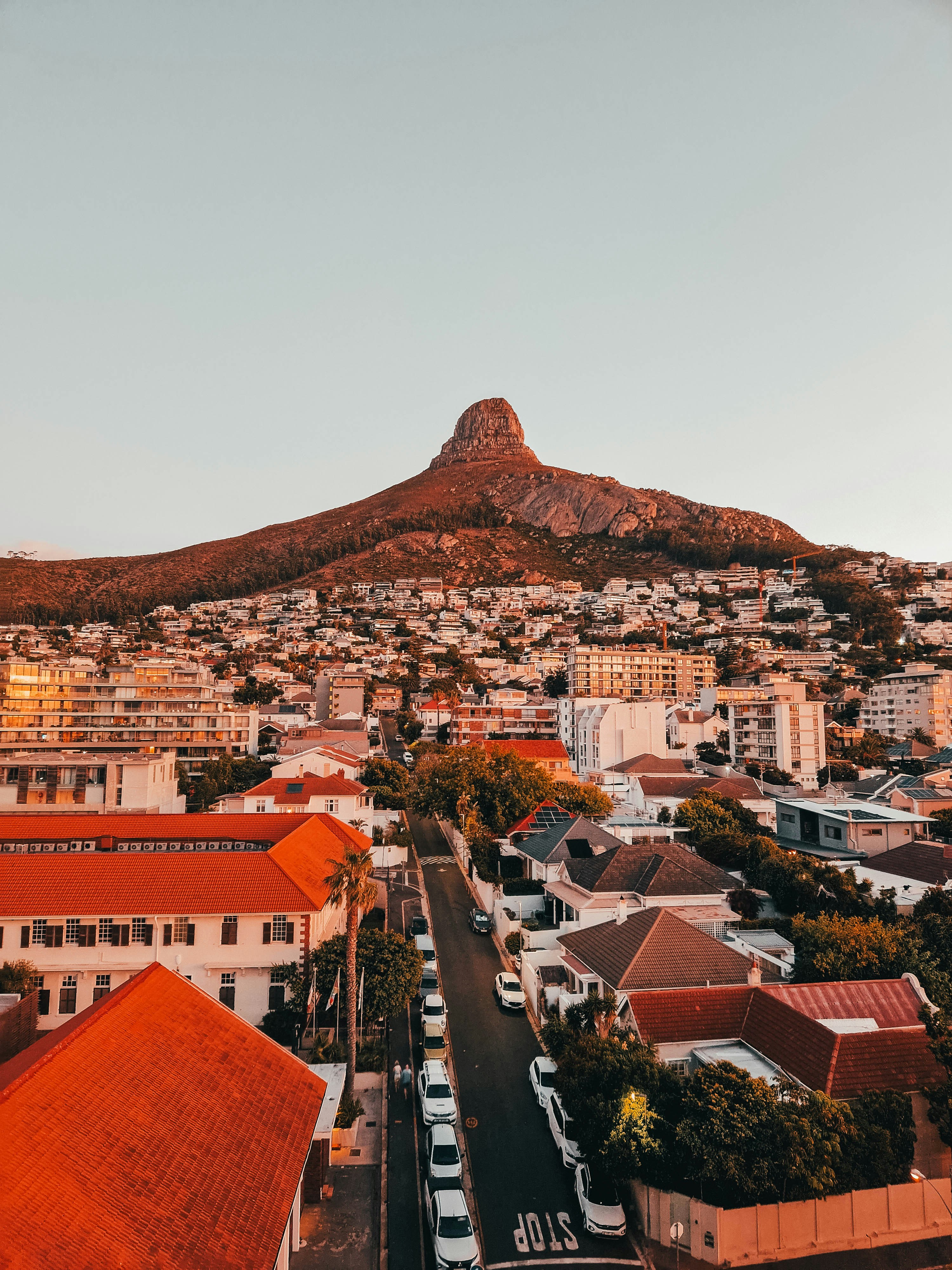 Cityscape with a prominent mountain peak in the background under warm evening light.