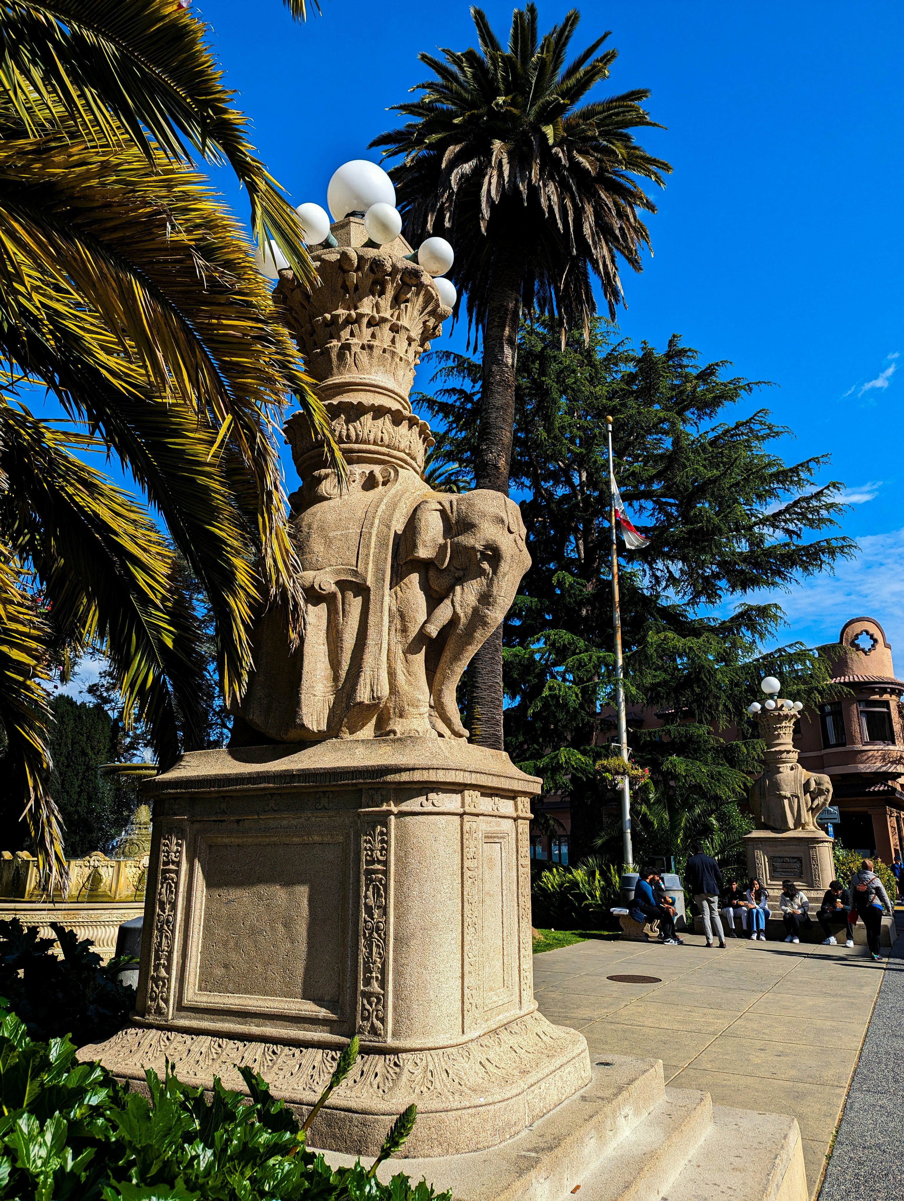 Sunlit Stone Lantern in a Palm-Lined Plaza: Elephant-Carved Pedestal