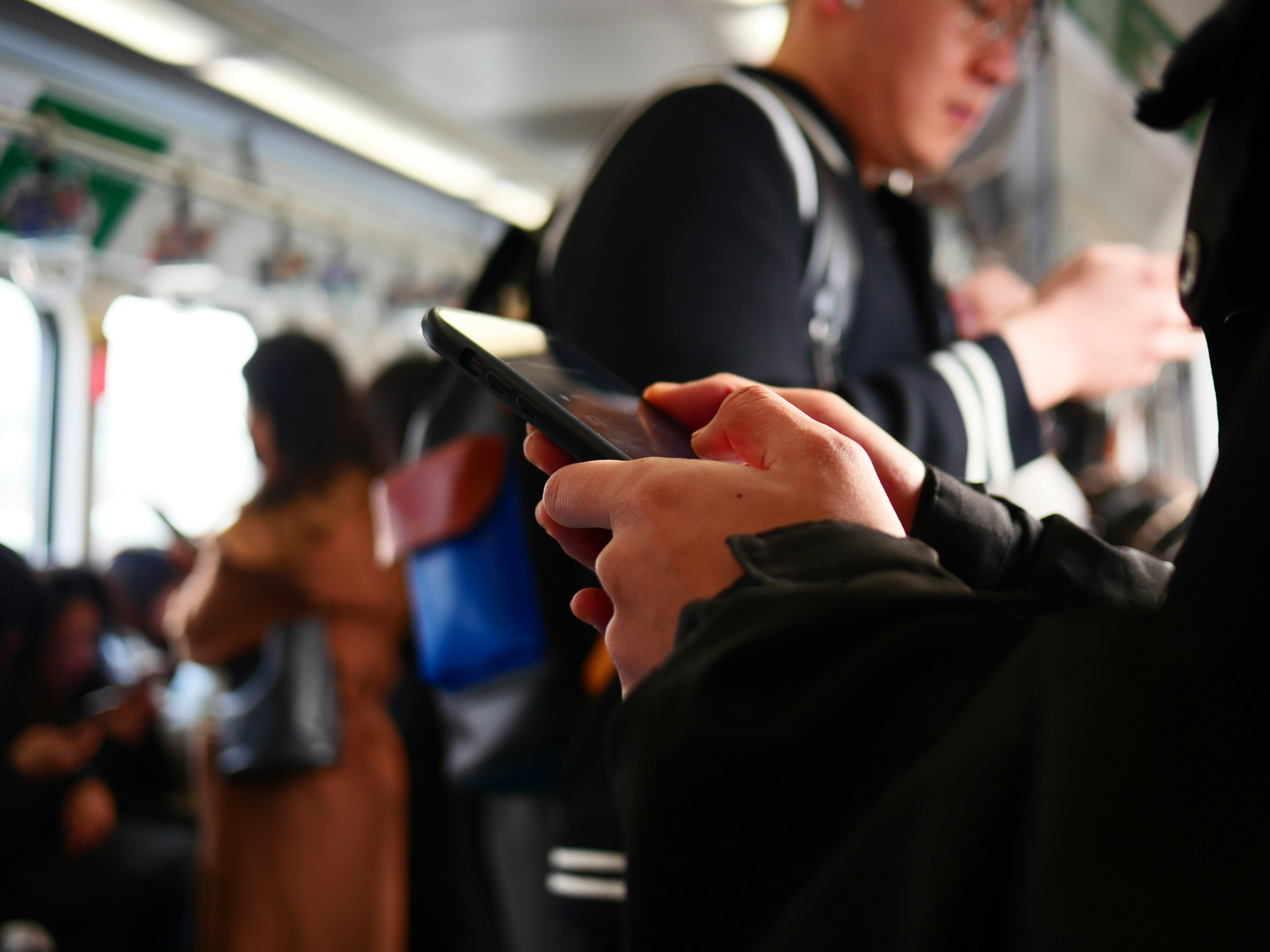 Commuters absorbed in their smartphones on a bustling subway ride.