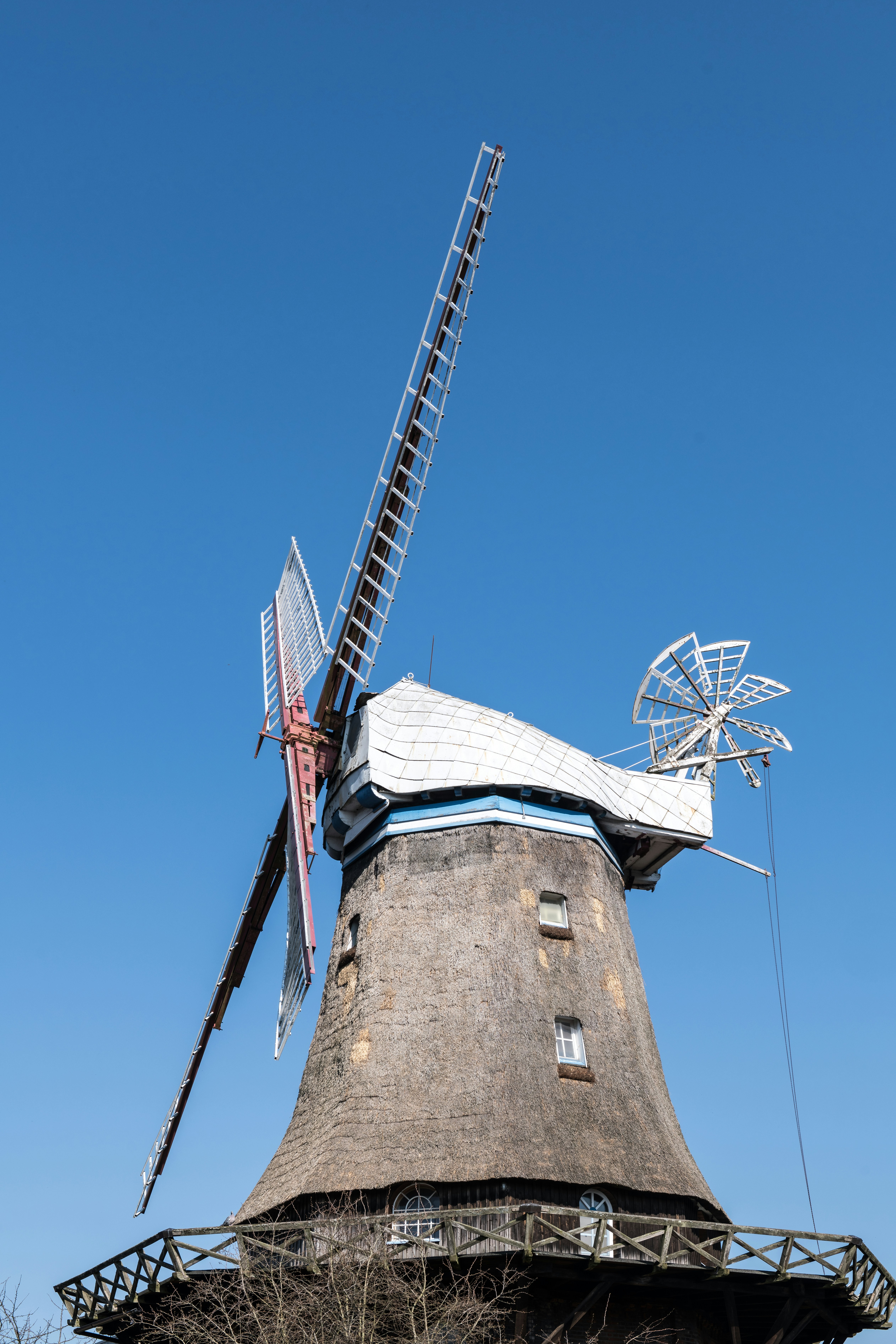 Azure Sky, Weathered Sails: A Classic Windmill Reaching for the Light