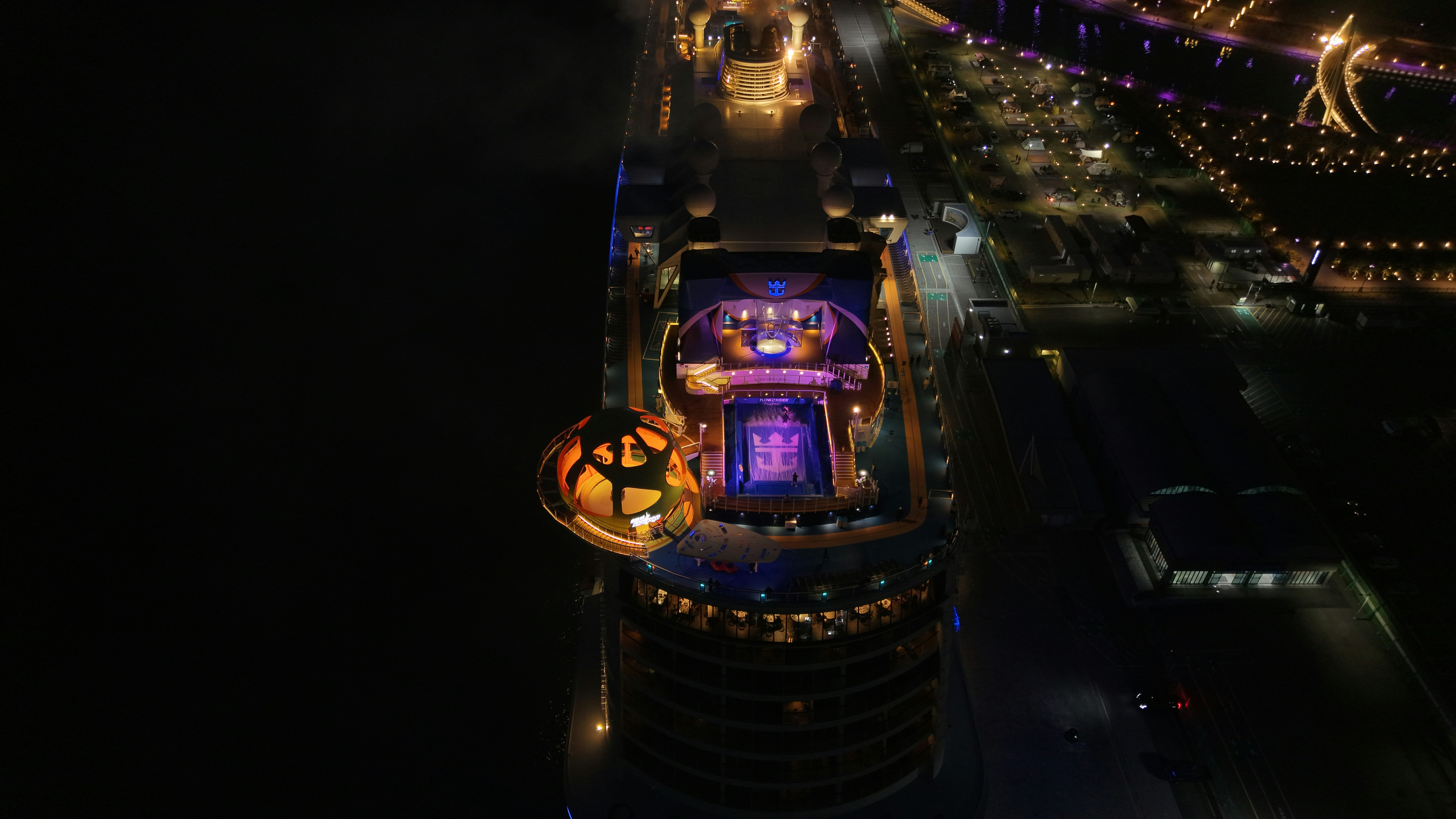 Neon Crest on Night Seas: Aerial View of a Purple-Lit Cruise Deck