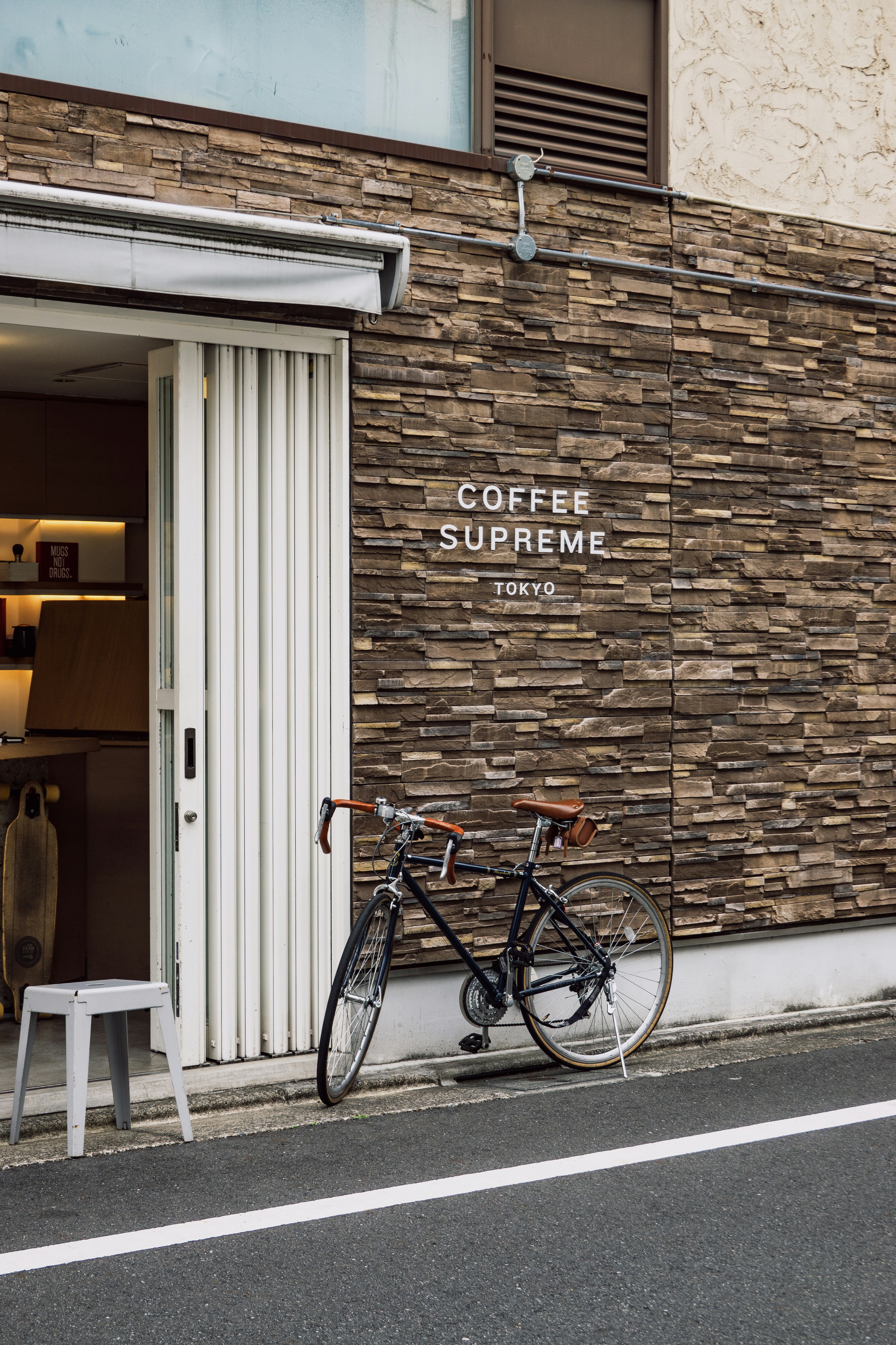 Stone-Walled Café Oasis: a bicycle rests beside Tokyo’s Coffee Supreme sign
