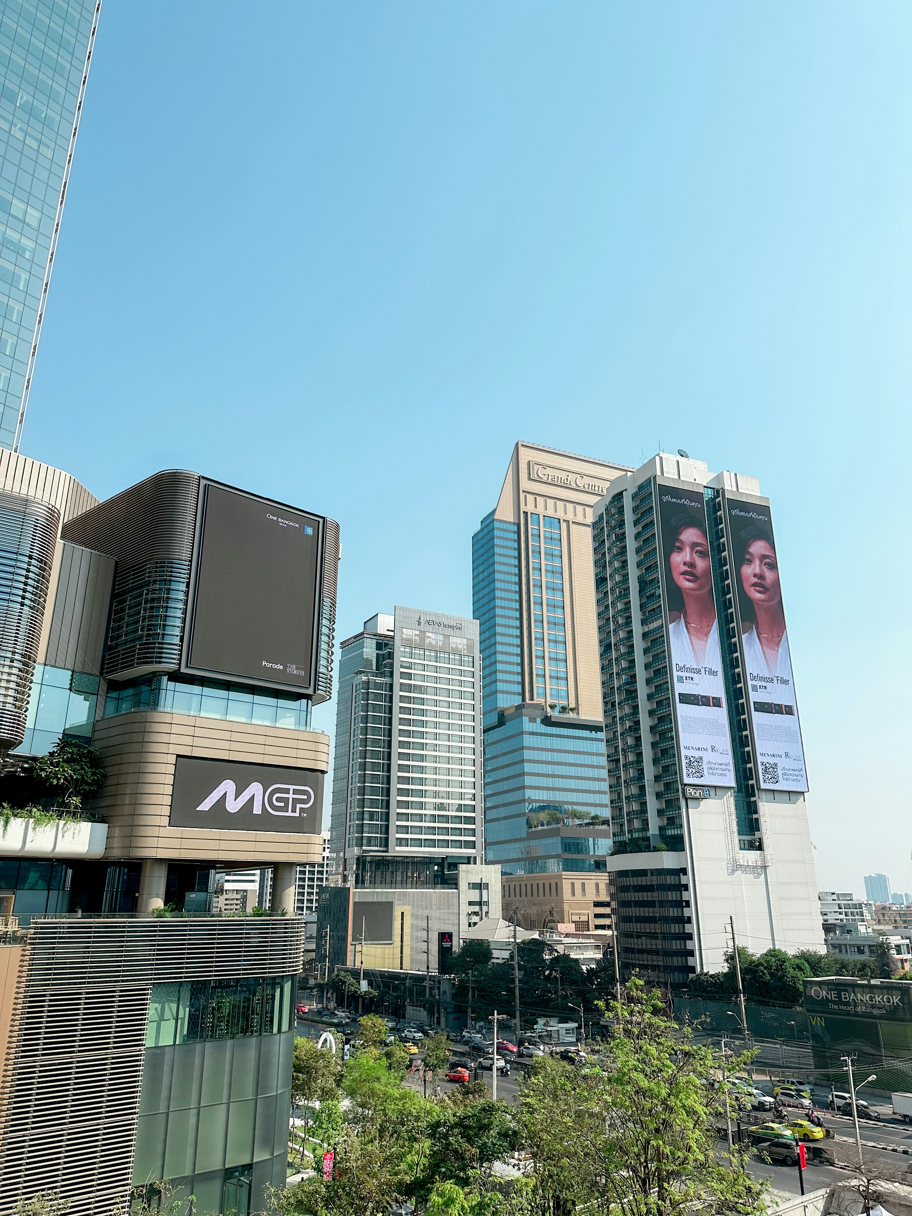 Modern skyscrapers rise against a clear blue sky in Bangkok's bustling downtown.