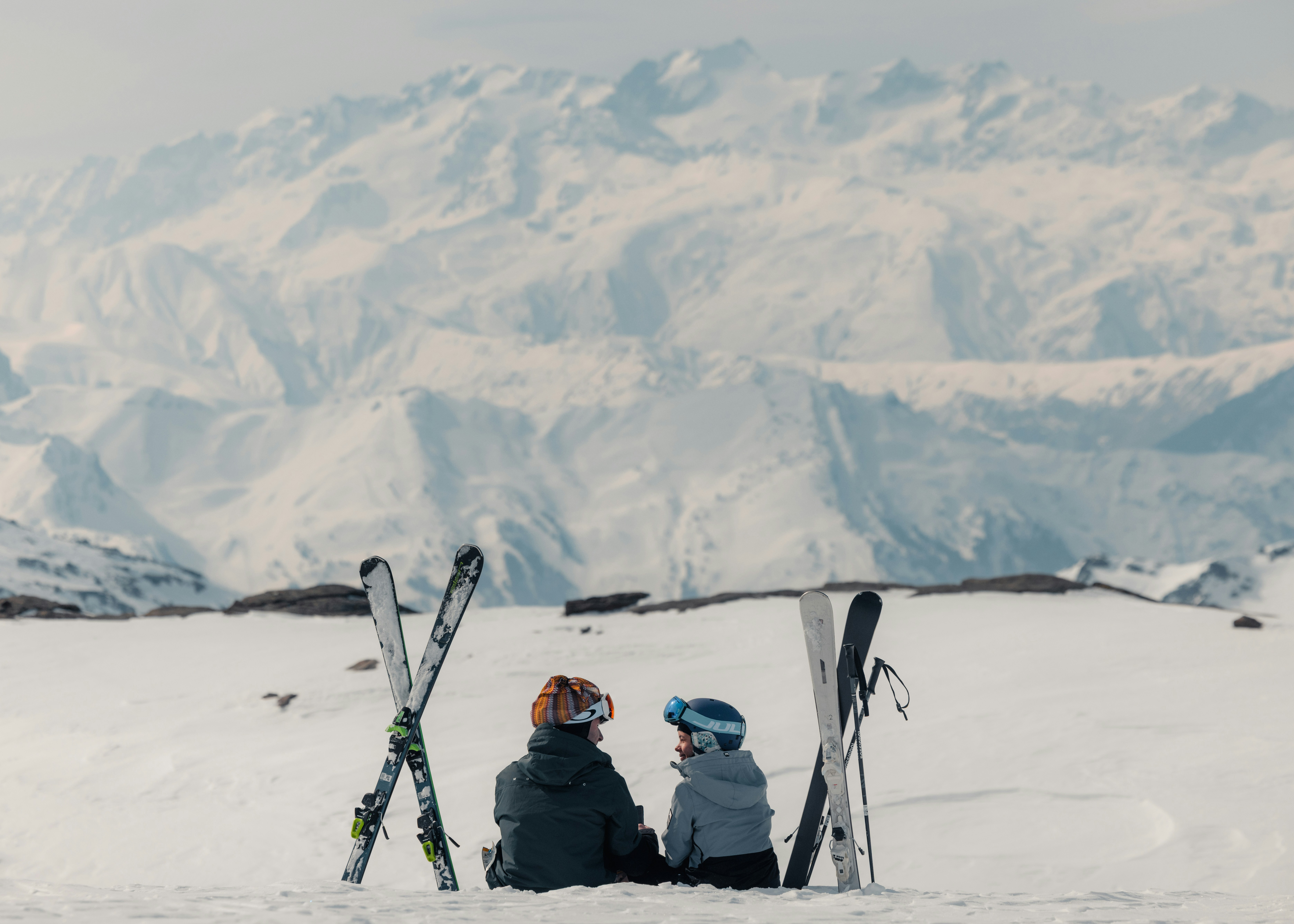 Two people admire snowy mountains with their skis. photo – Free ...