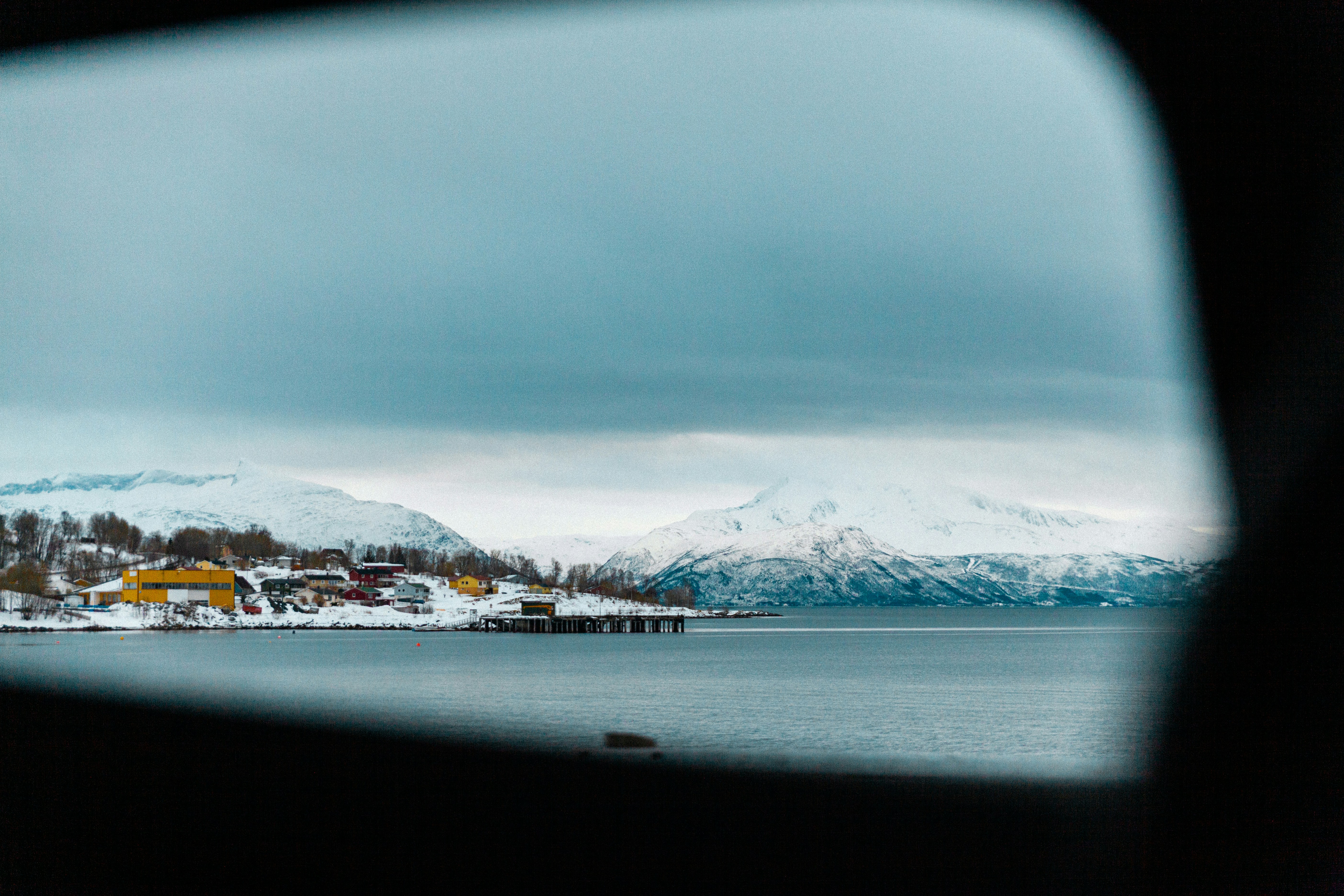 Snowbound Fjord Village: The Bright Yellow Building Framed by a Dark Window