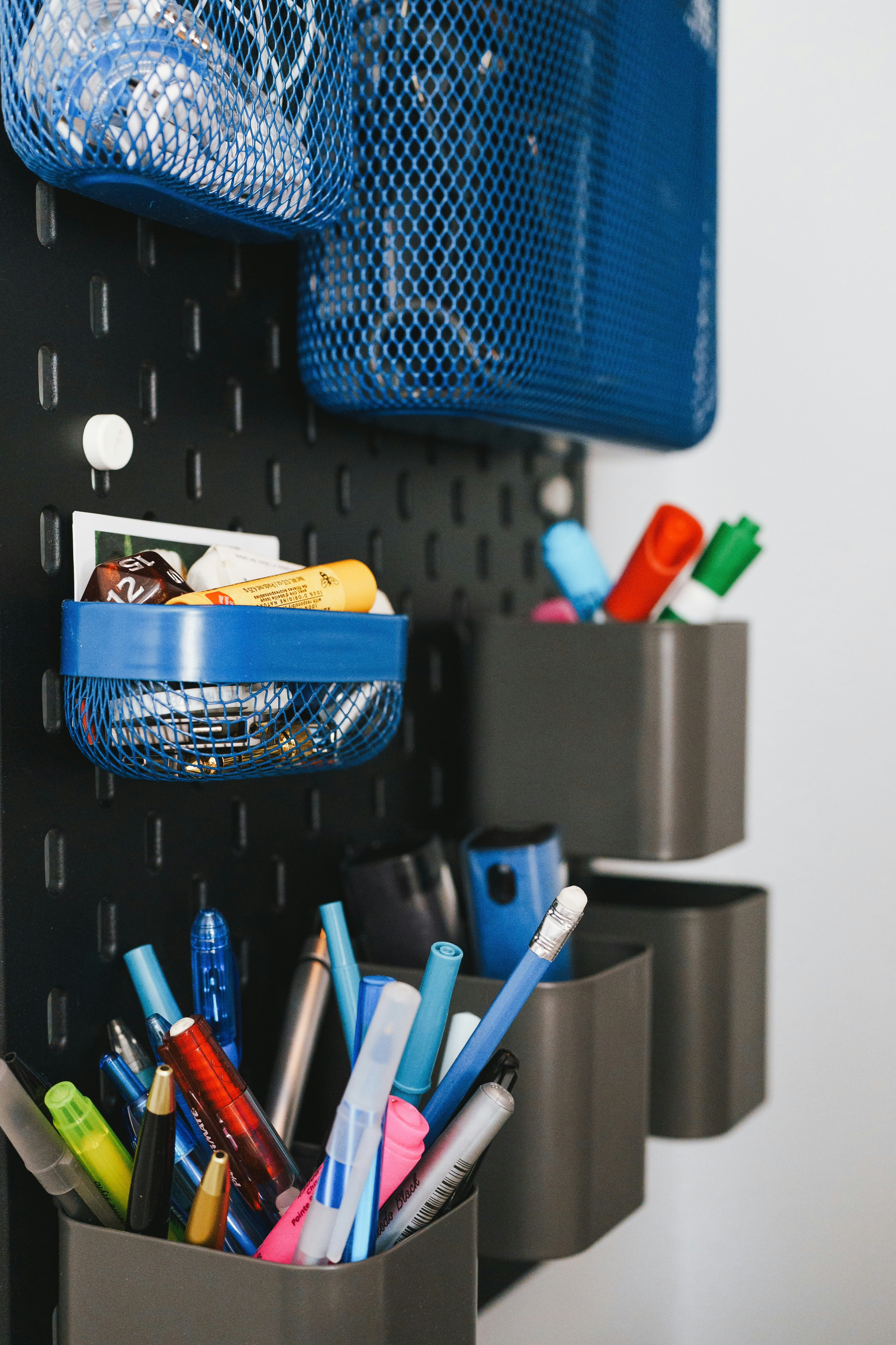 Blue Mesh Basket Anchors a Multicolor Desk Organizer on a Pegboard