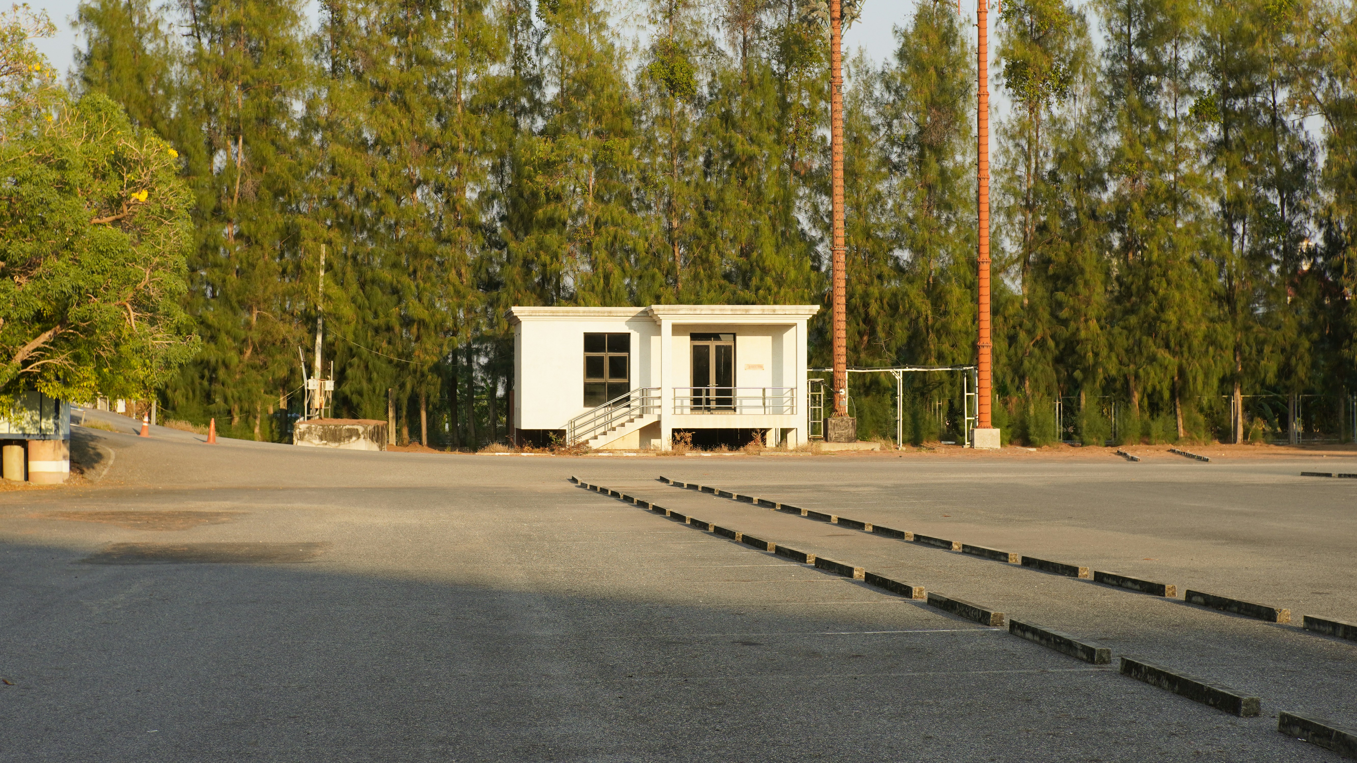 Guardhouse at the Edge: A Sunlit Parking Lot’s Quiet Geometry