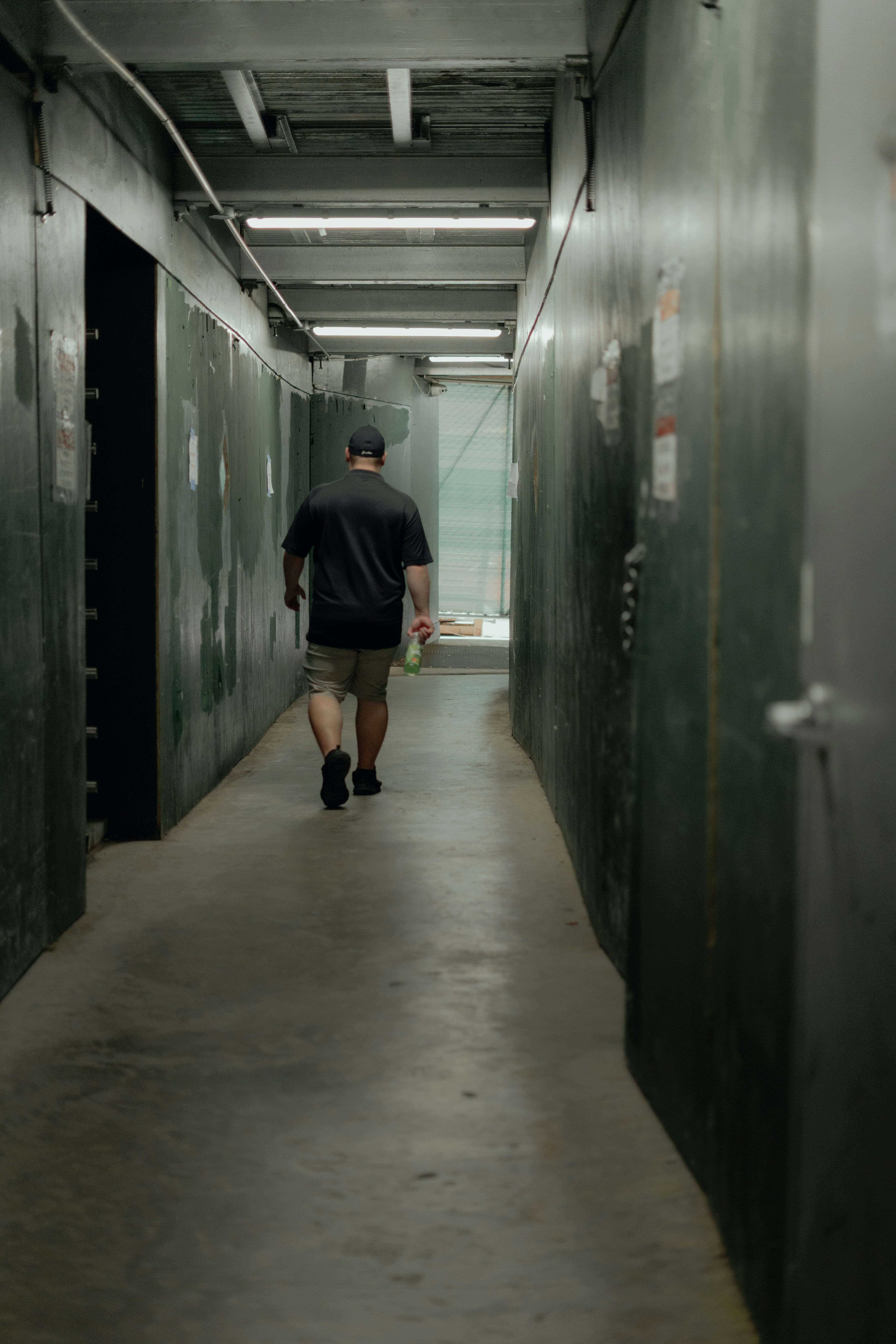 A man walks down a long, dim hallway. photo – Free City Image on Unsplash