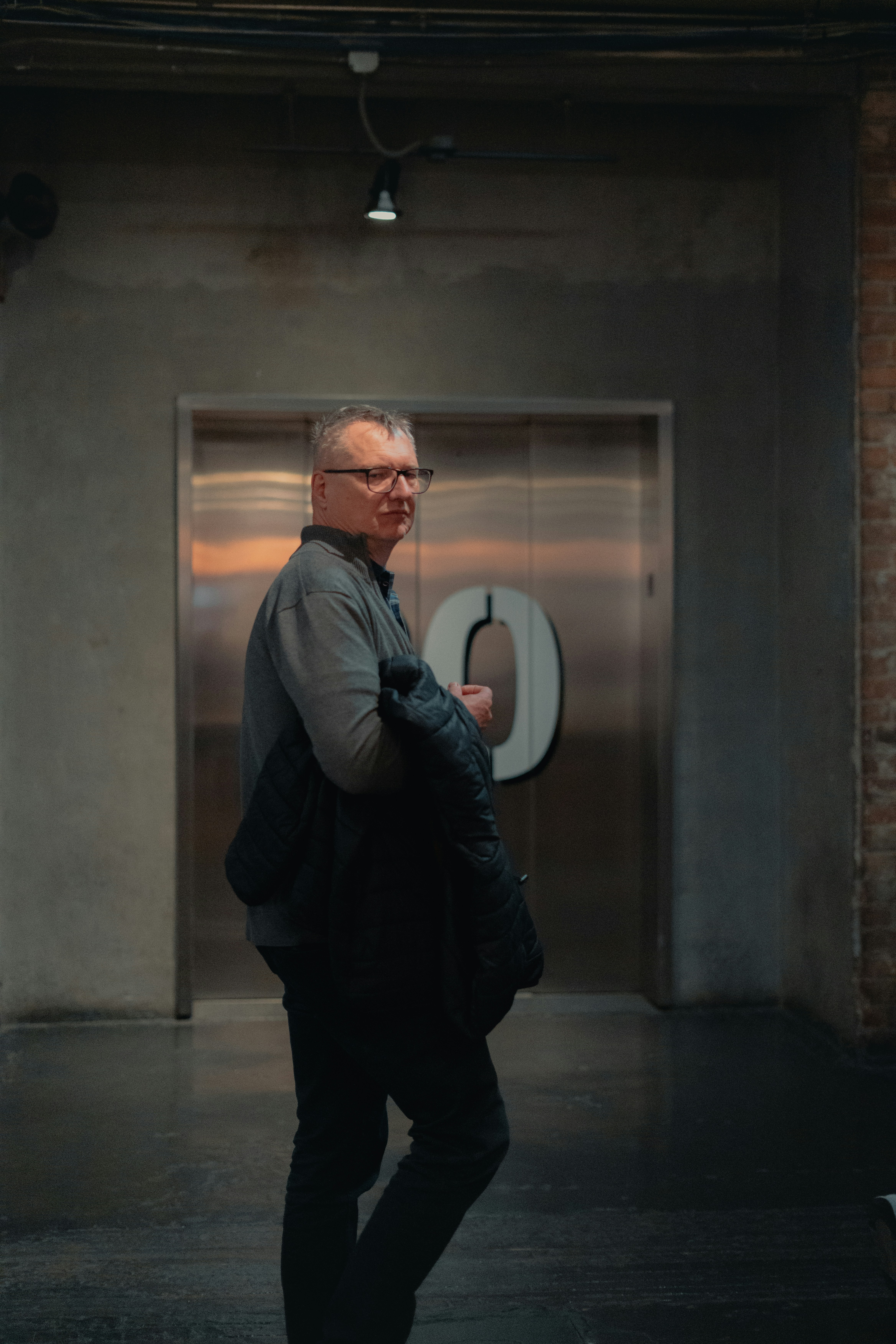 Man stands near an elevator with a large "0" on it. photo – Free ...