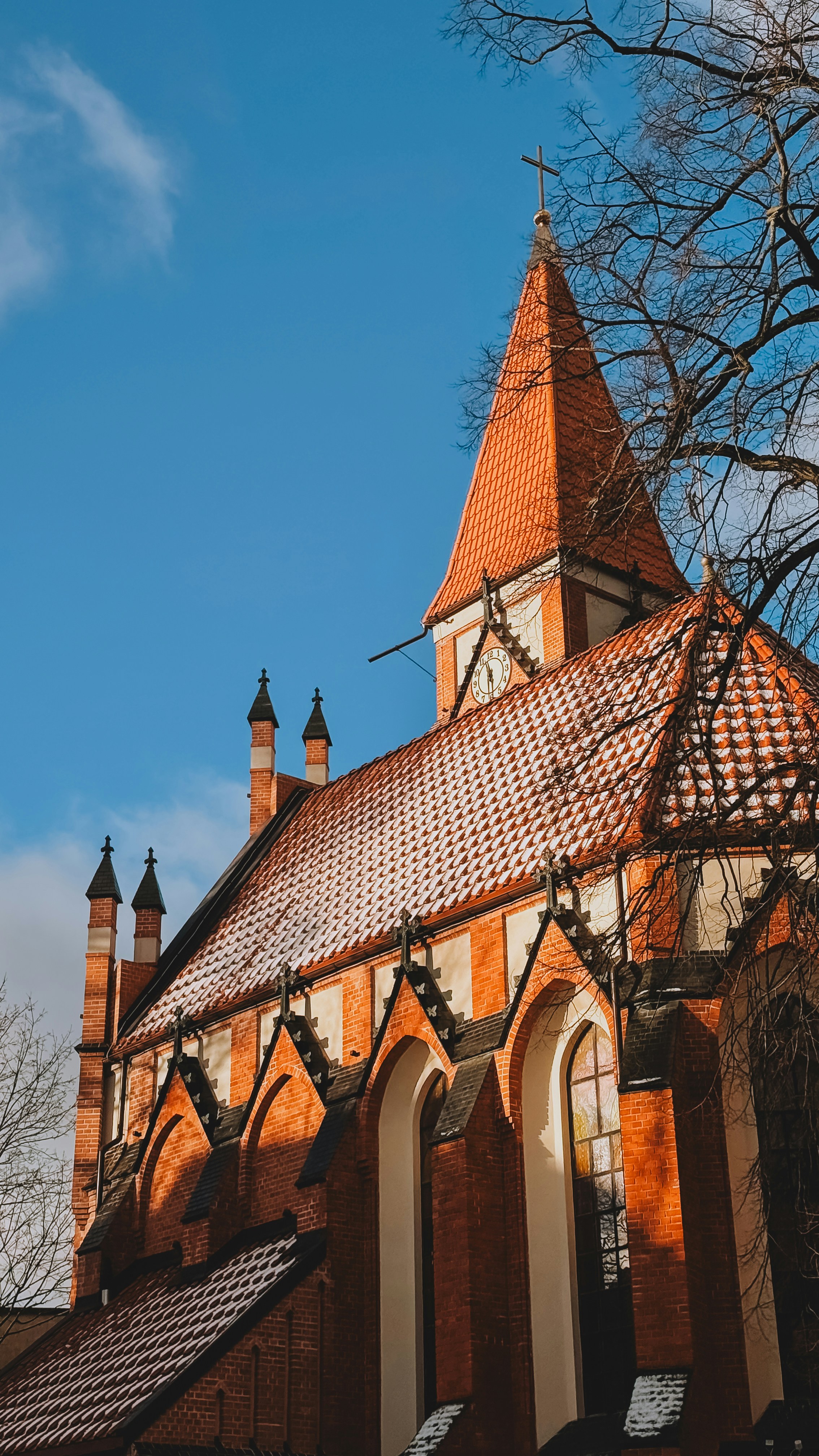 Cross-Topped Clock Tower Cast in Winter Light on a Brick Gothic Church
