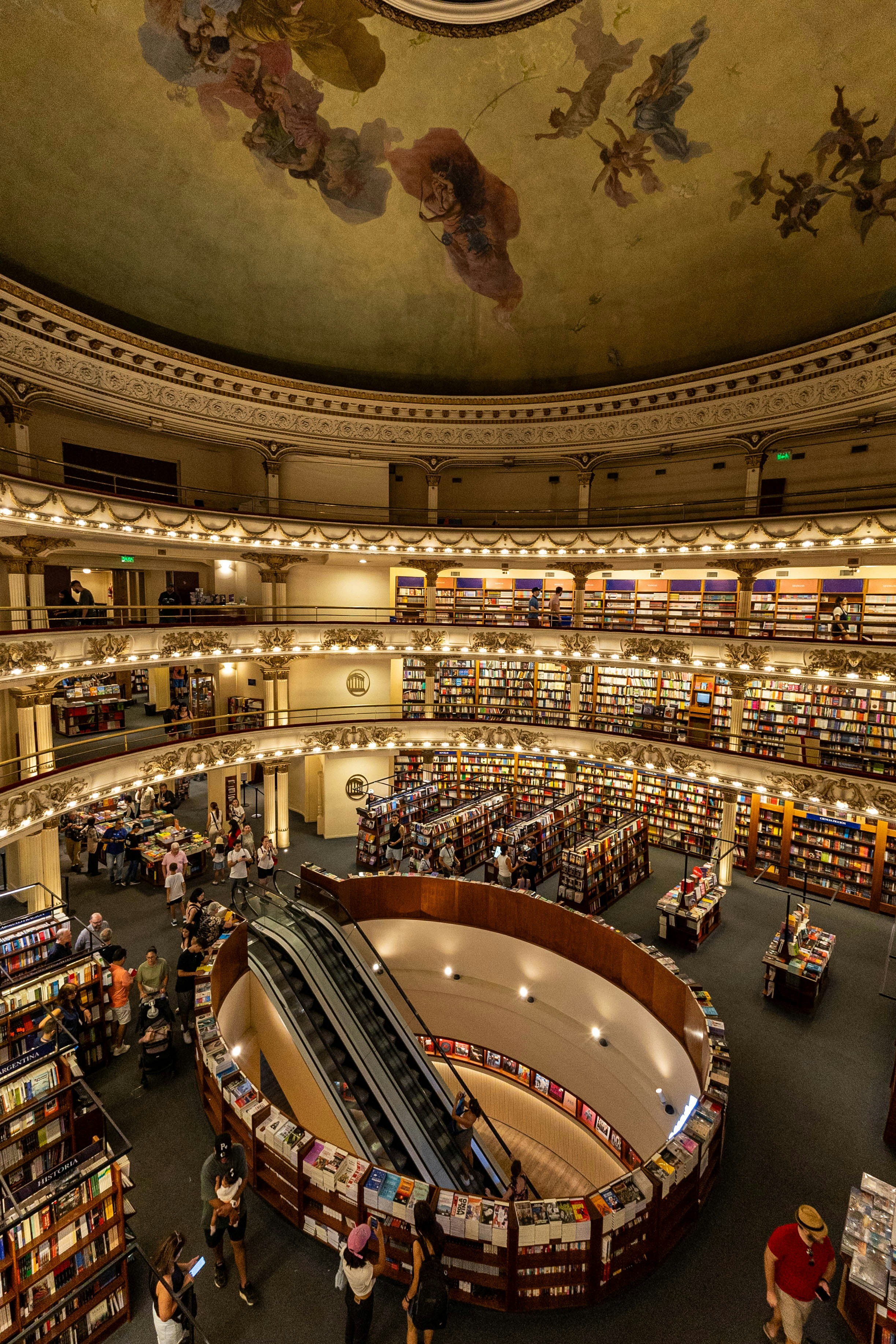 Grand bookstore interior with ornate balconies and frescoed ceiling, showcasing rows of books and a central staircase.