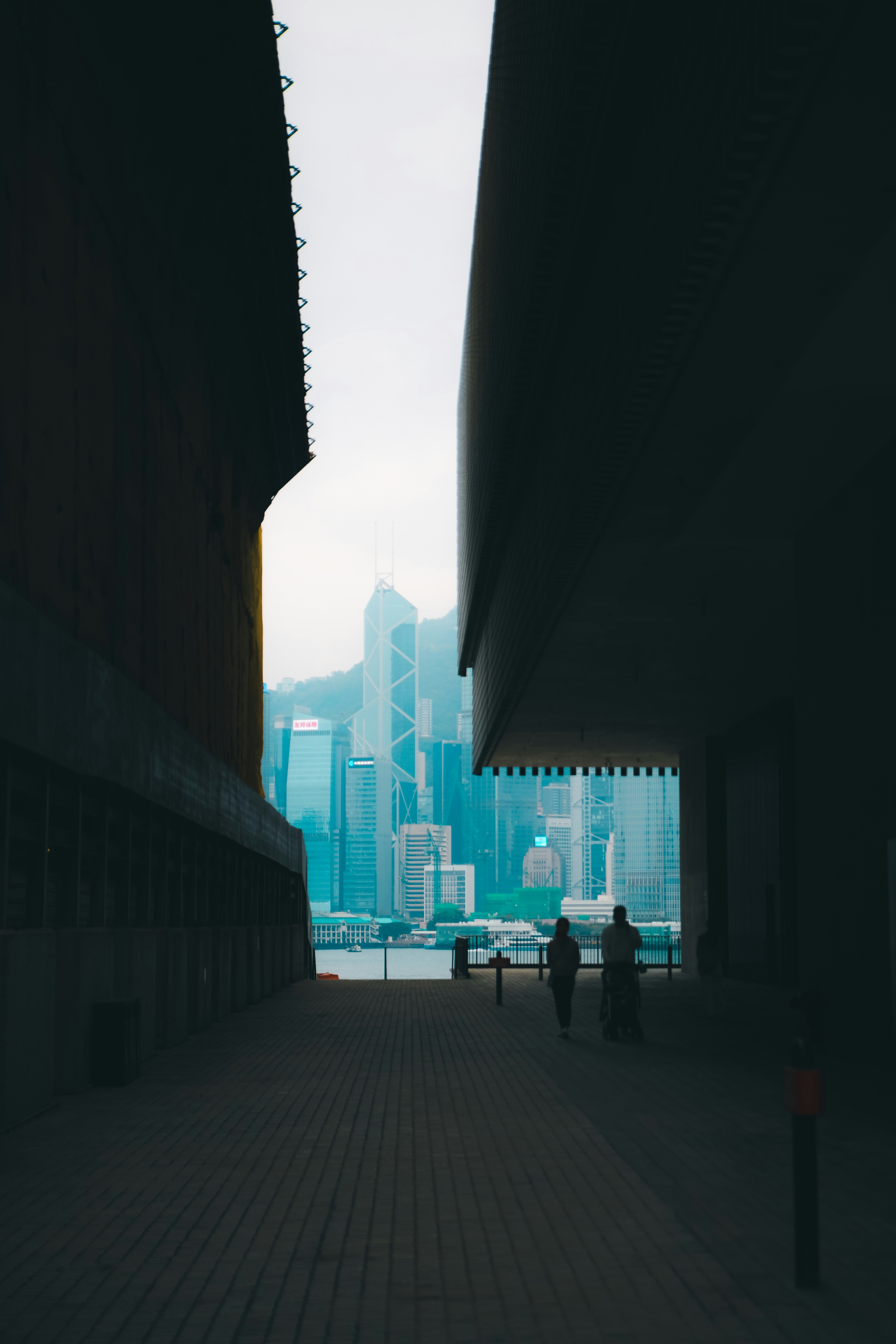A walkway framed by buildings reveals city skyline. photo – Free Human ...