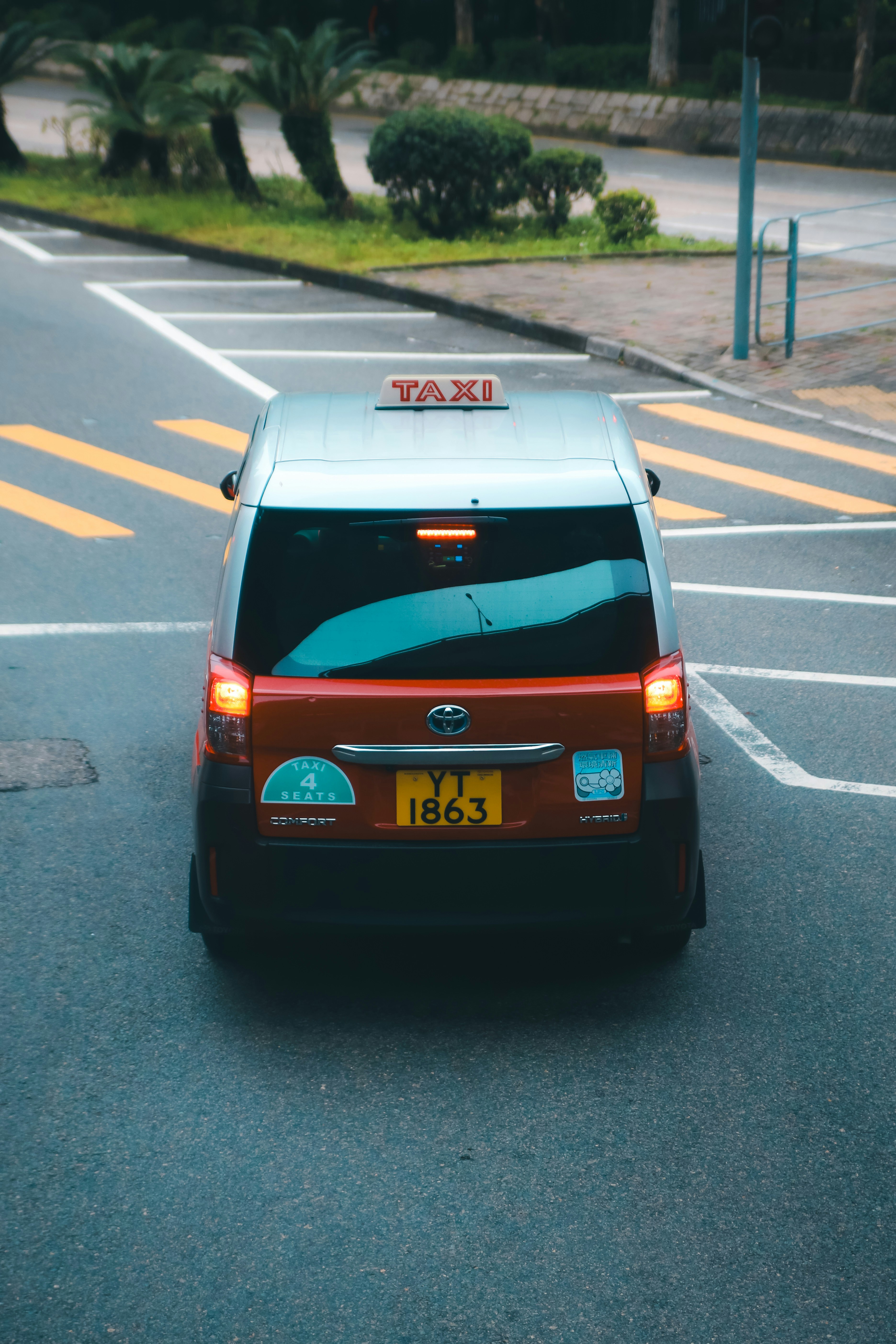 Taxi navigating a Hong Kong street intersection, surrounded by crosswalks and greenery.