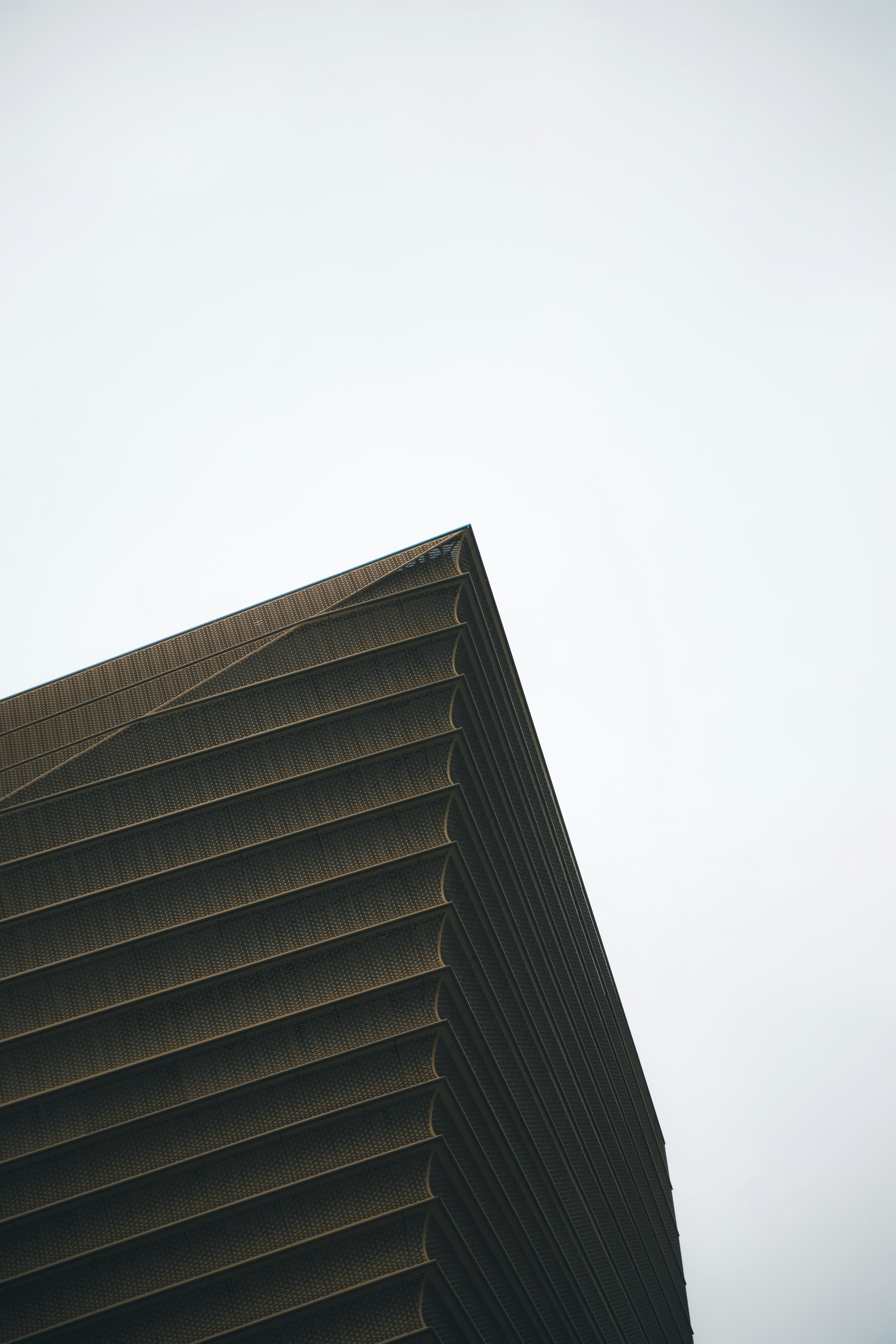 La esquina de un edificio moderno contra un cielo gris. foto – Imagen ...