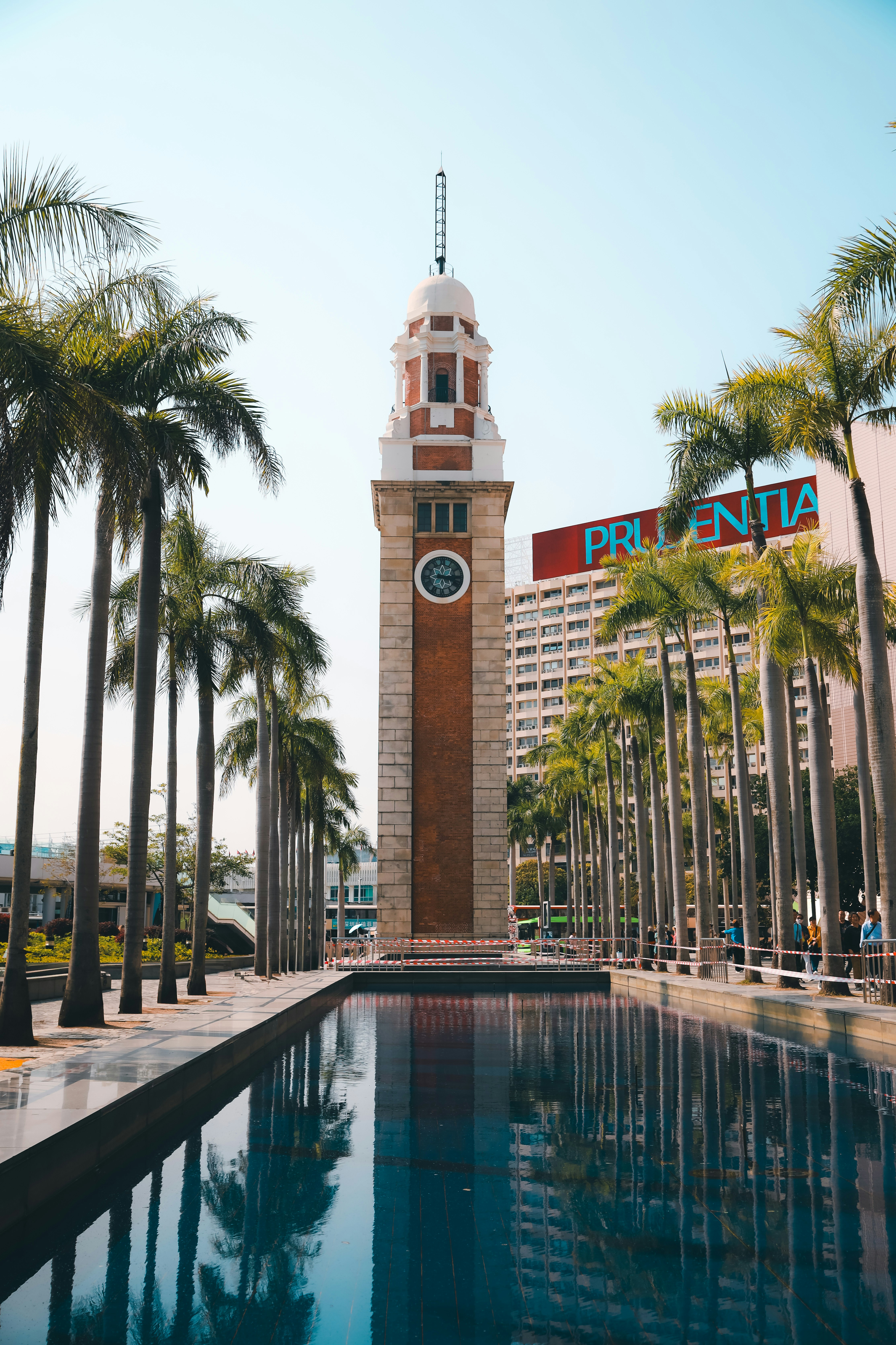 A tall clock tower is reflected in the water. photo – Free Hong kong ...