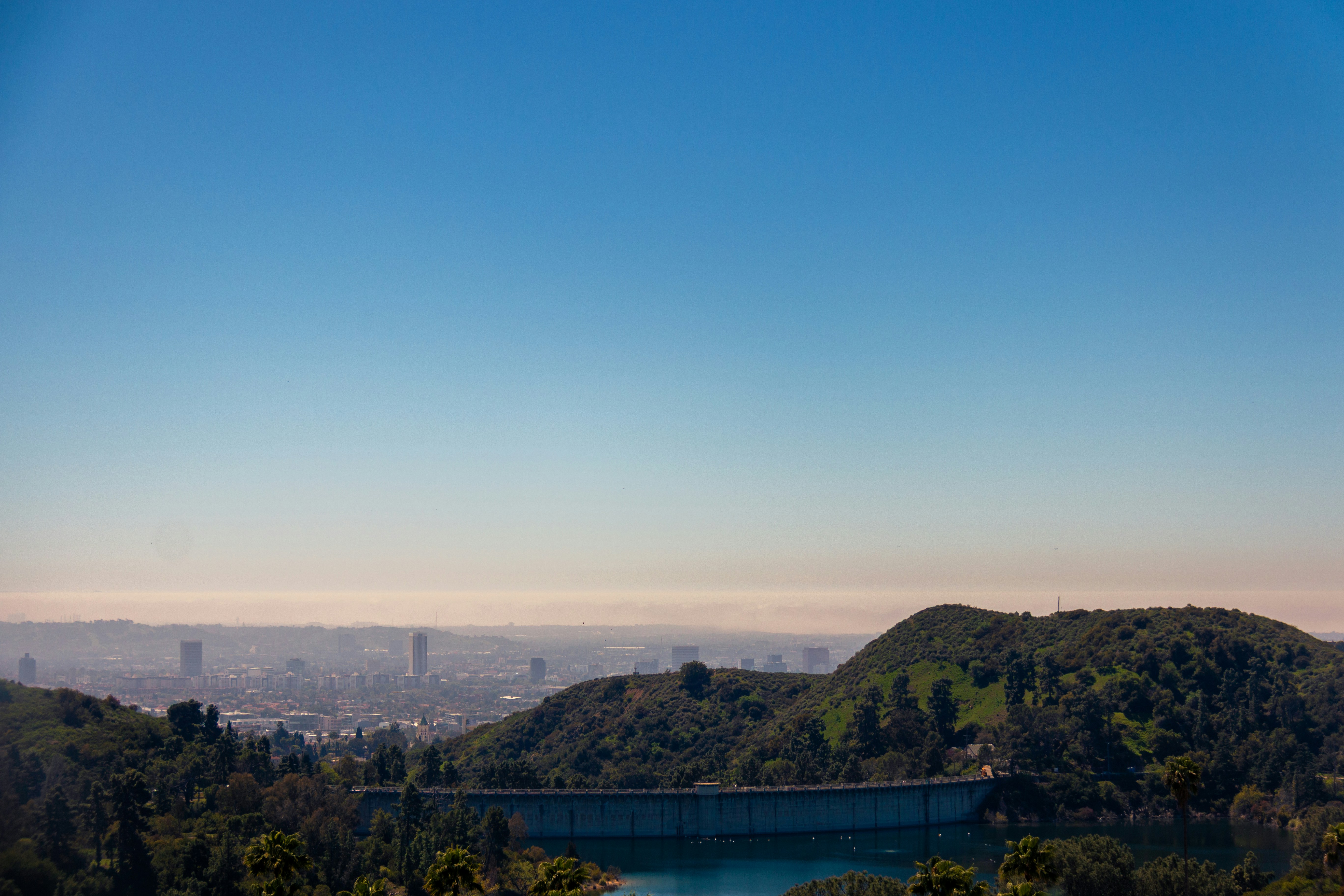 Distant city view with hilly forest and bright sky.