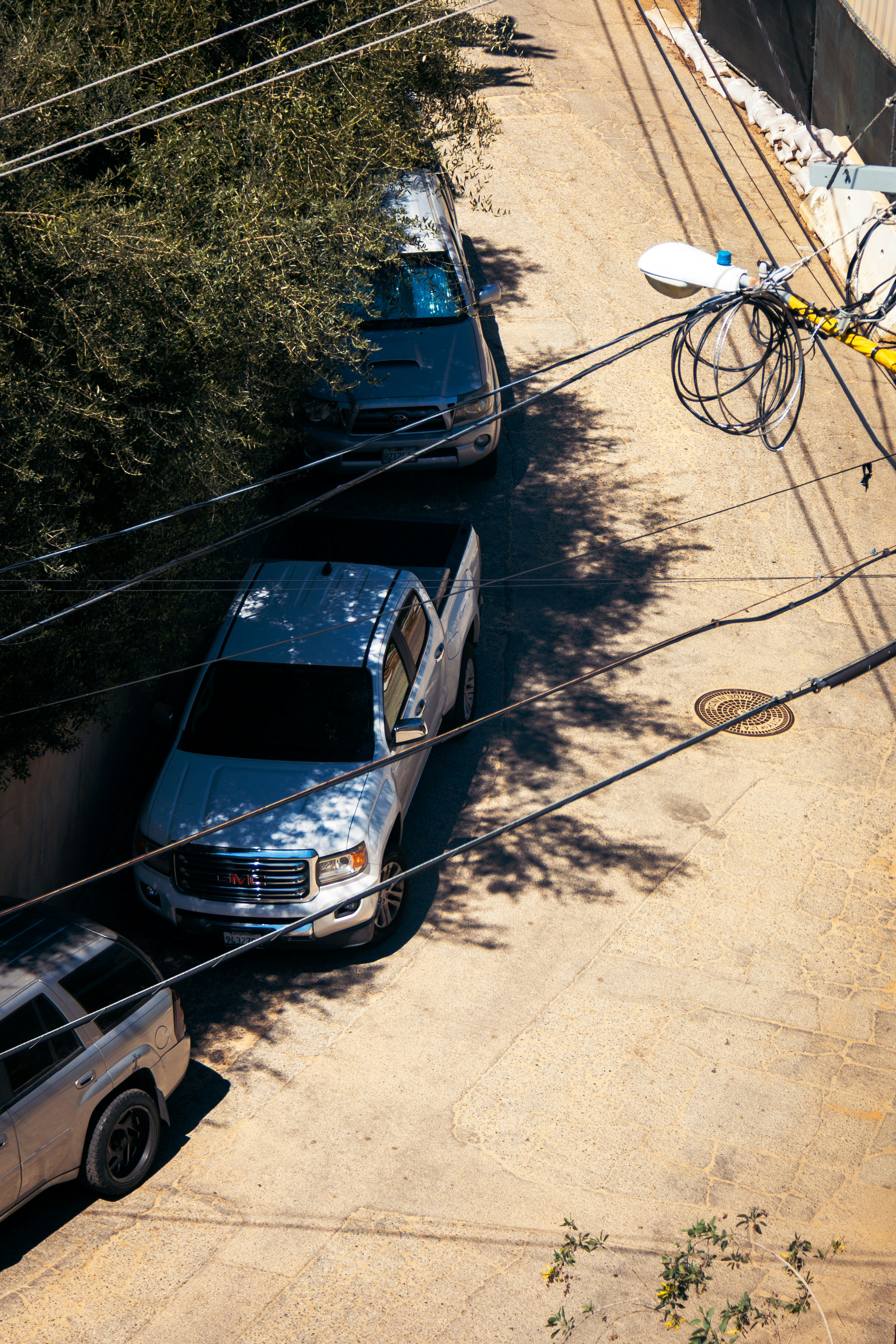 Crisscrossed Canopy Over a Sunlit Alley of Parked Trucks