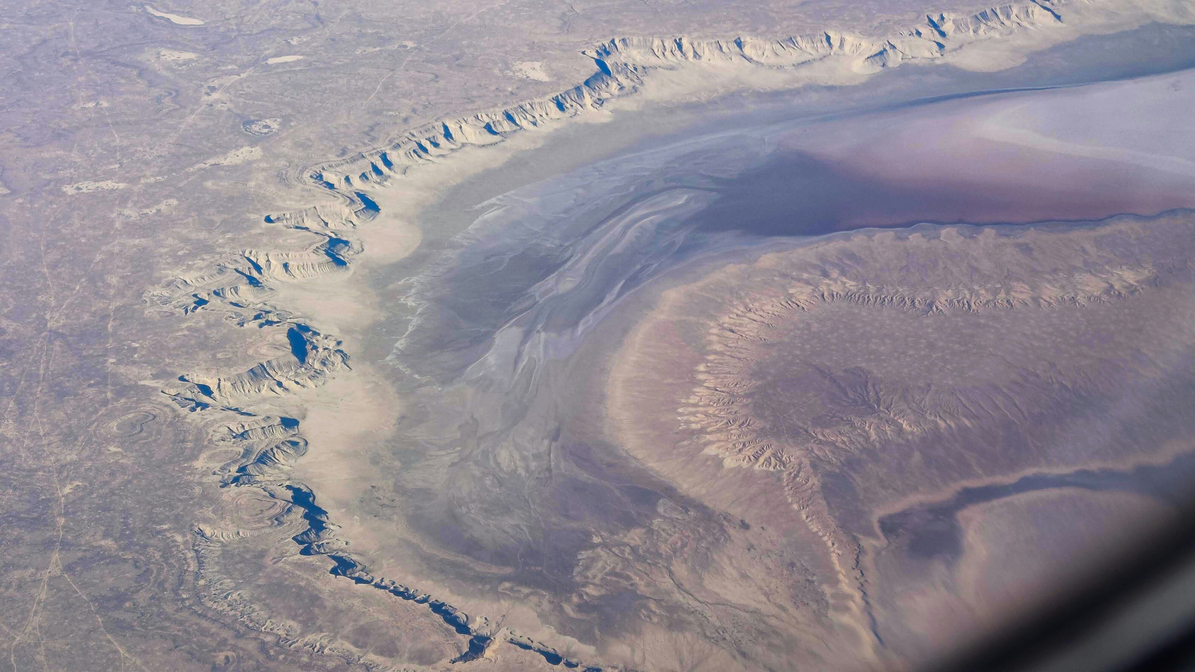 Aerial landscape showcasing a vast desert with winding formations and varied textures.