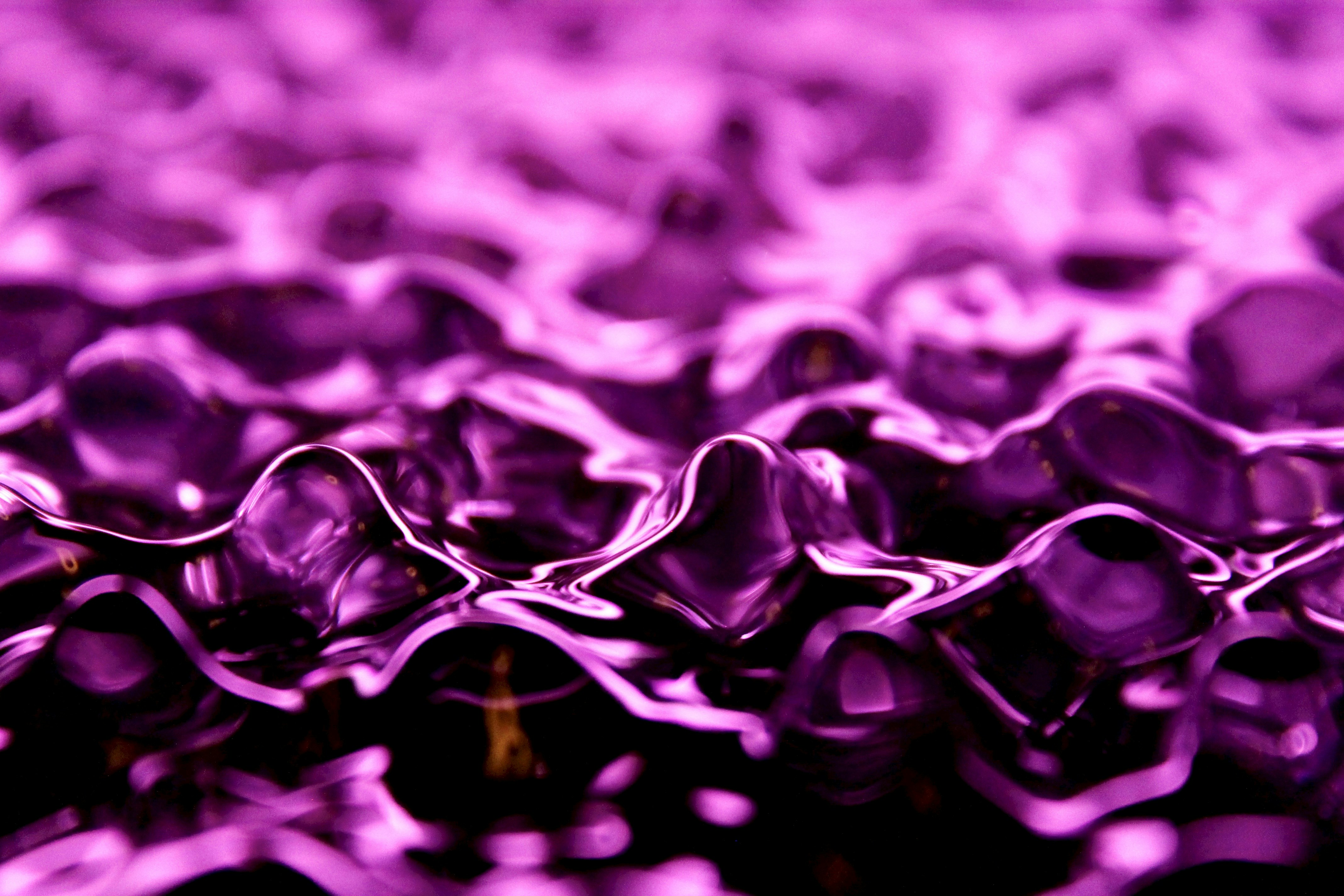 Close-up of a glossy, magenta bubble texture forming an abstract, liquid landscape.