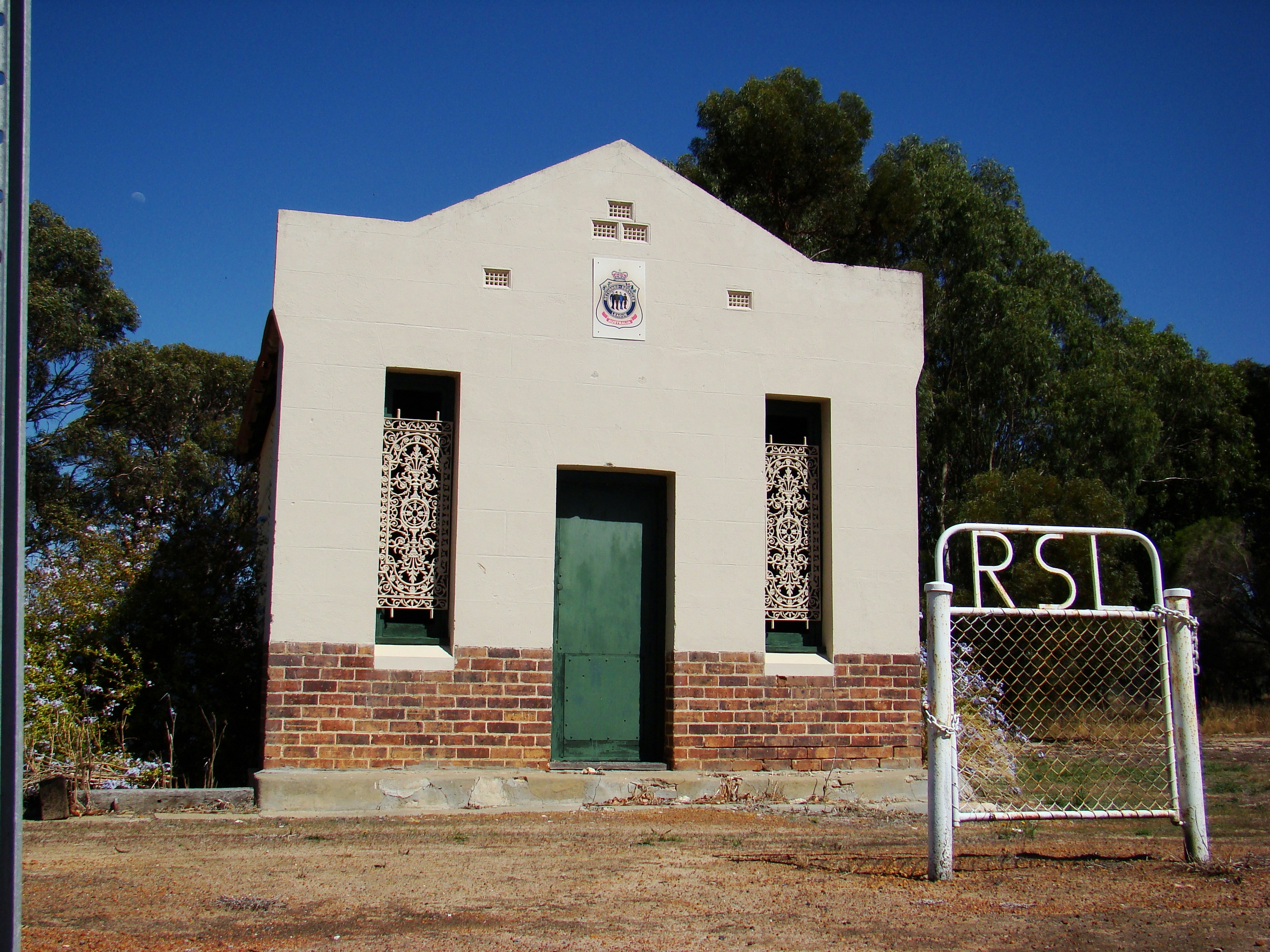 RSL building in a rural Australian town with a green door and brick foundation under a clear sky.