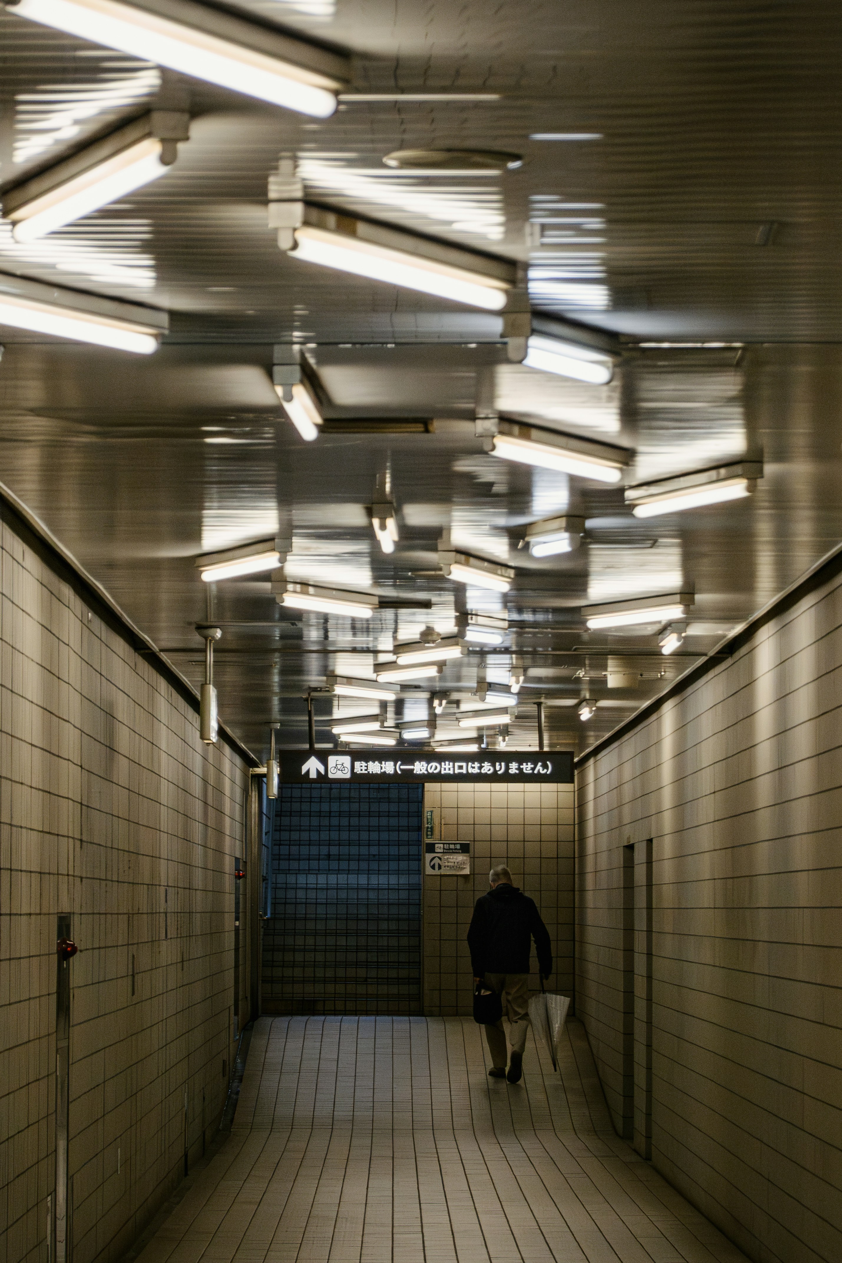 End of the Line: A solitary traveler in a fluorescent subway corridor