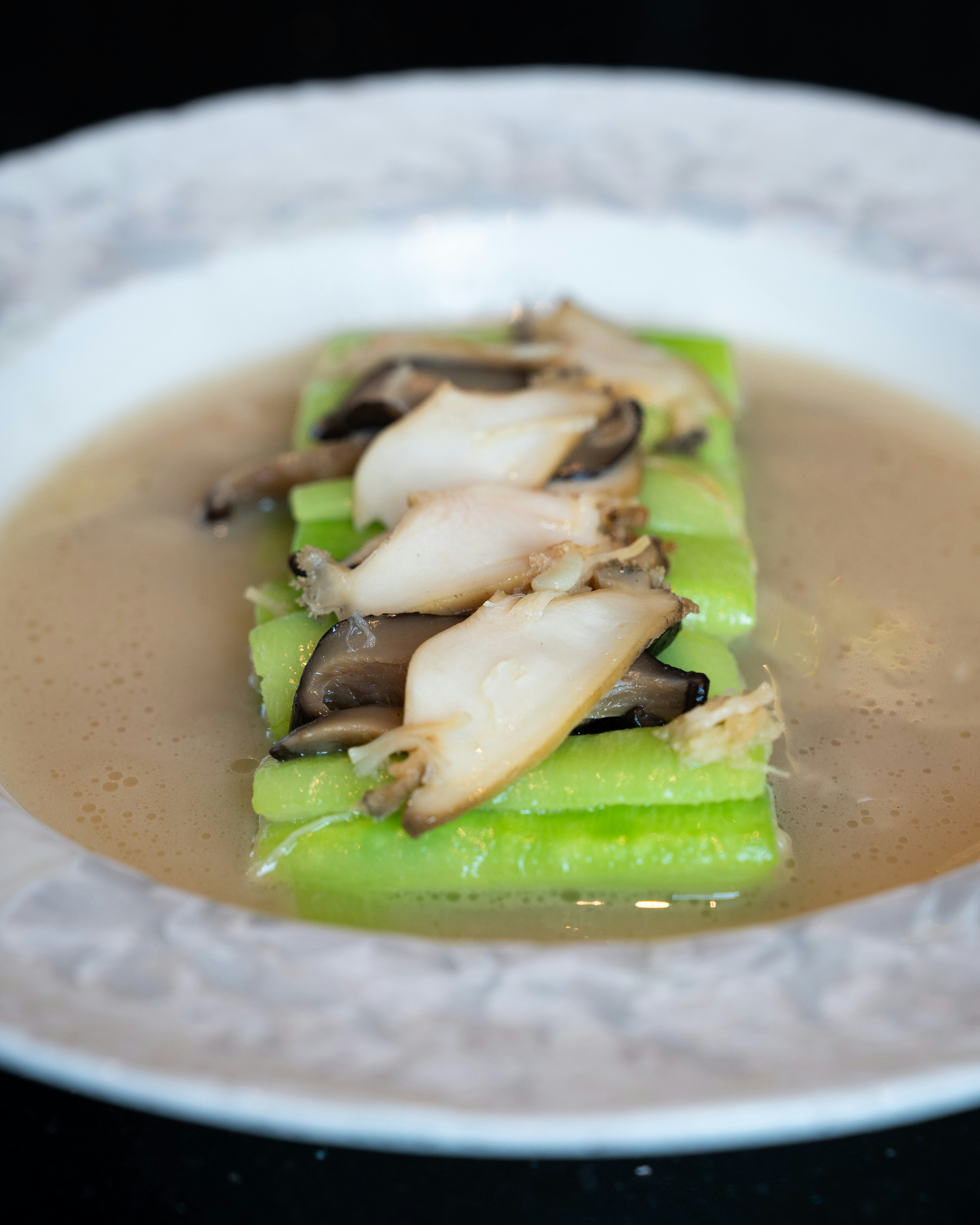 Mushroom-topped green wafer stack in velvety broth