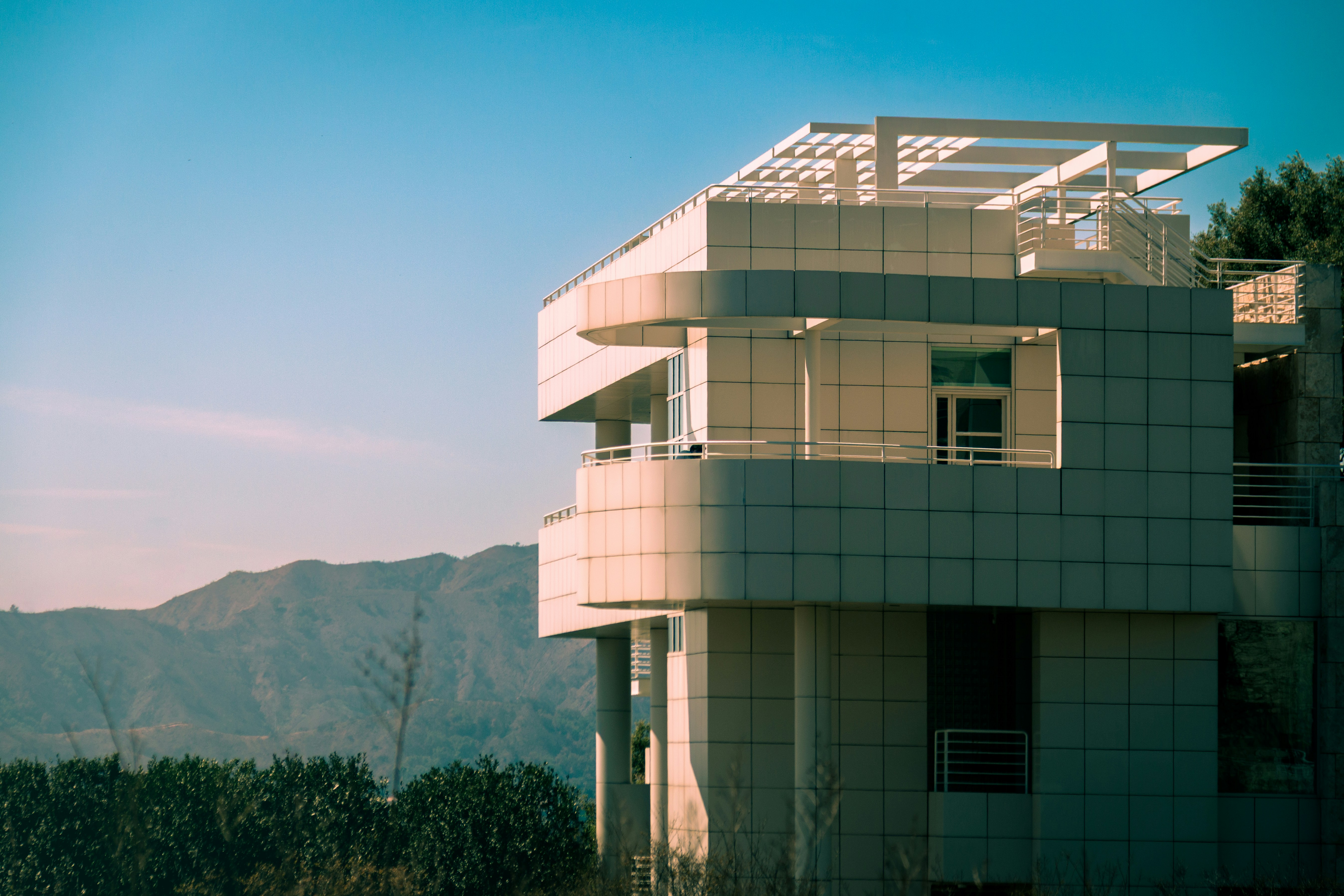 Modern building with angular design set against distant hills under a clear blue sky.