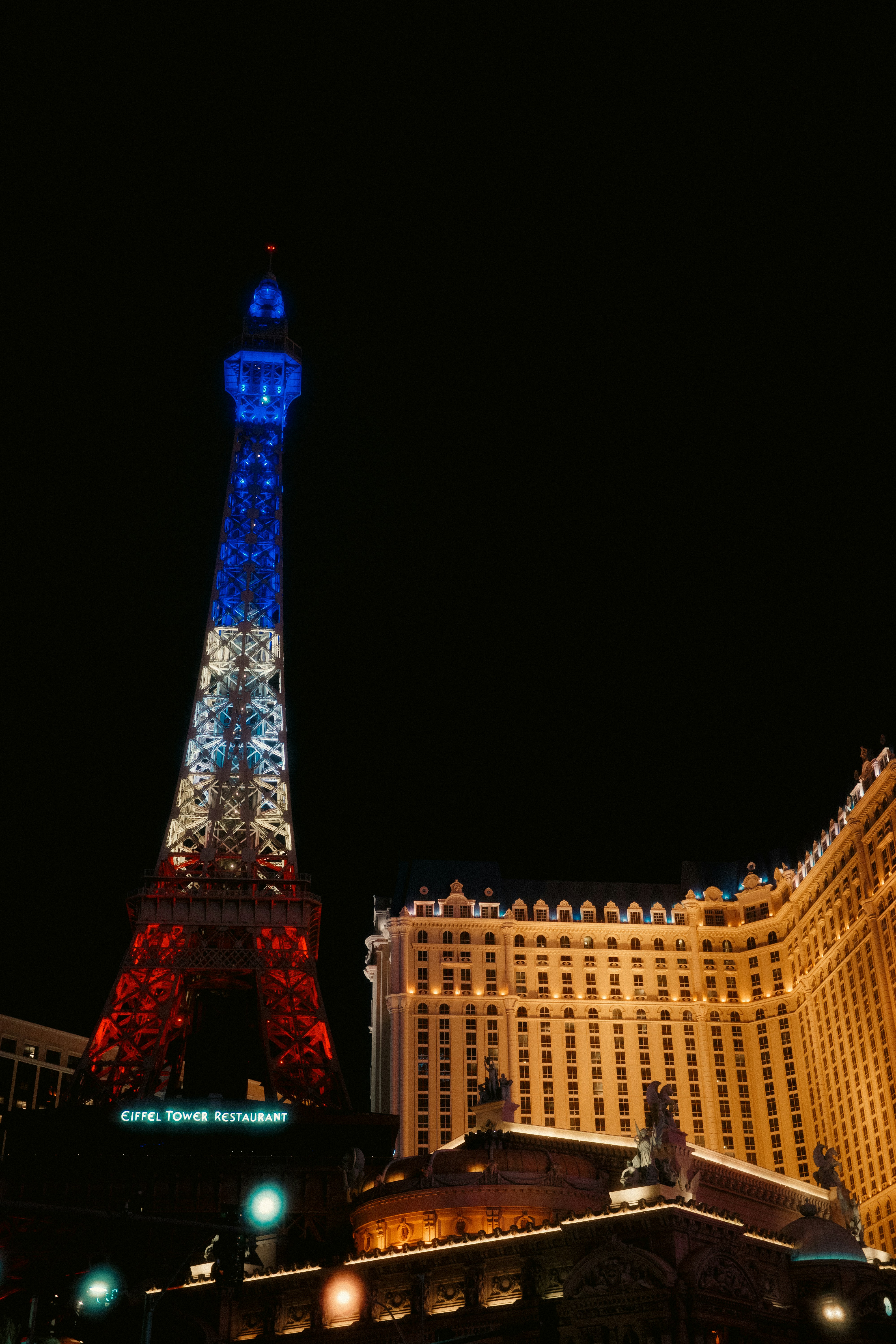 Illuminated Eiffel Tower and grand hotel skyline at night