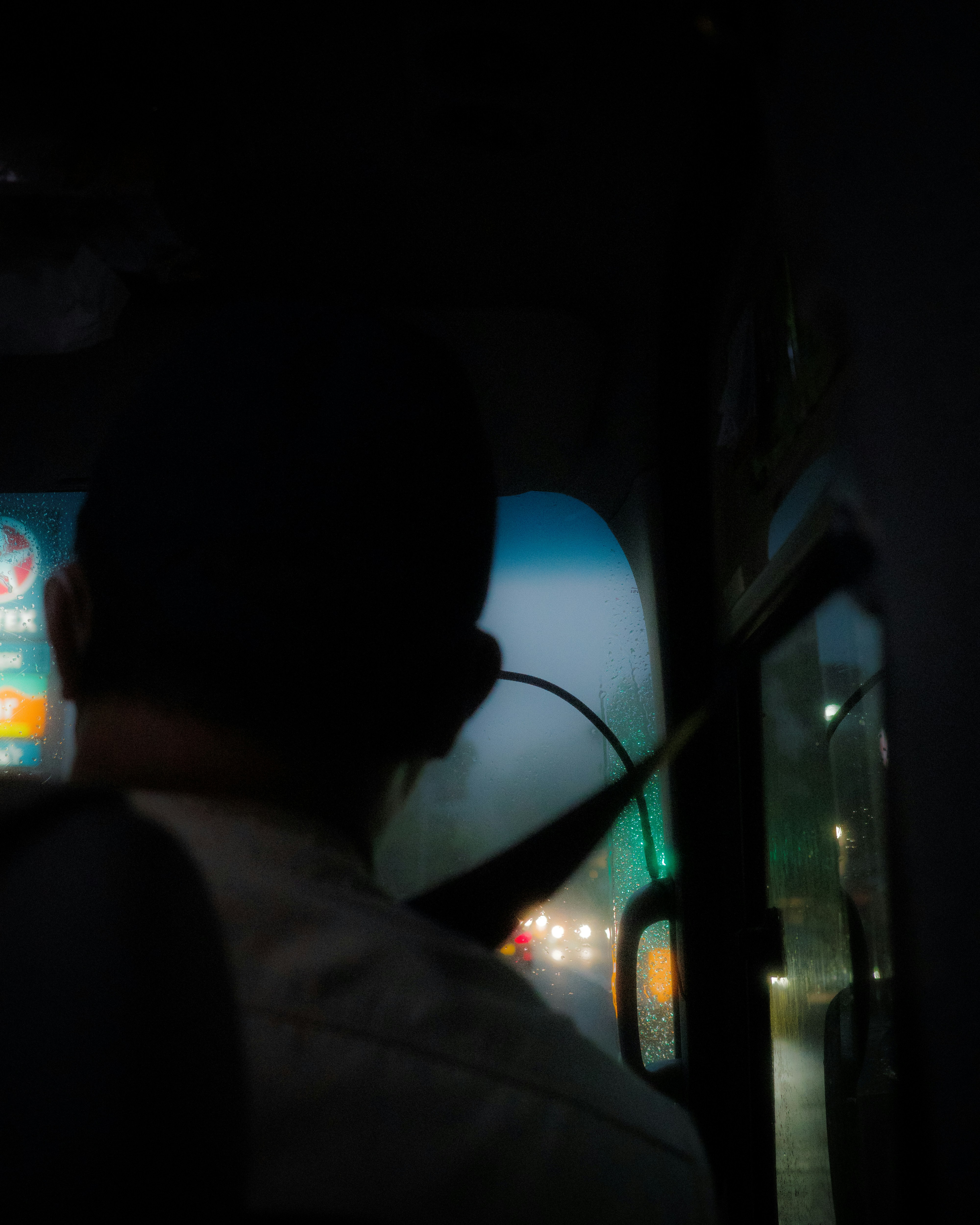 A person sits in a dimly lit vehicle.