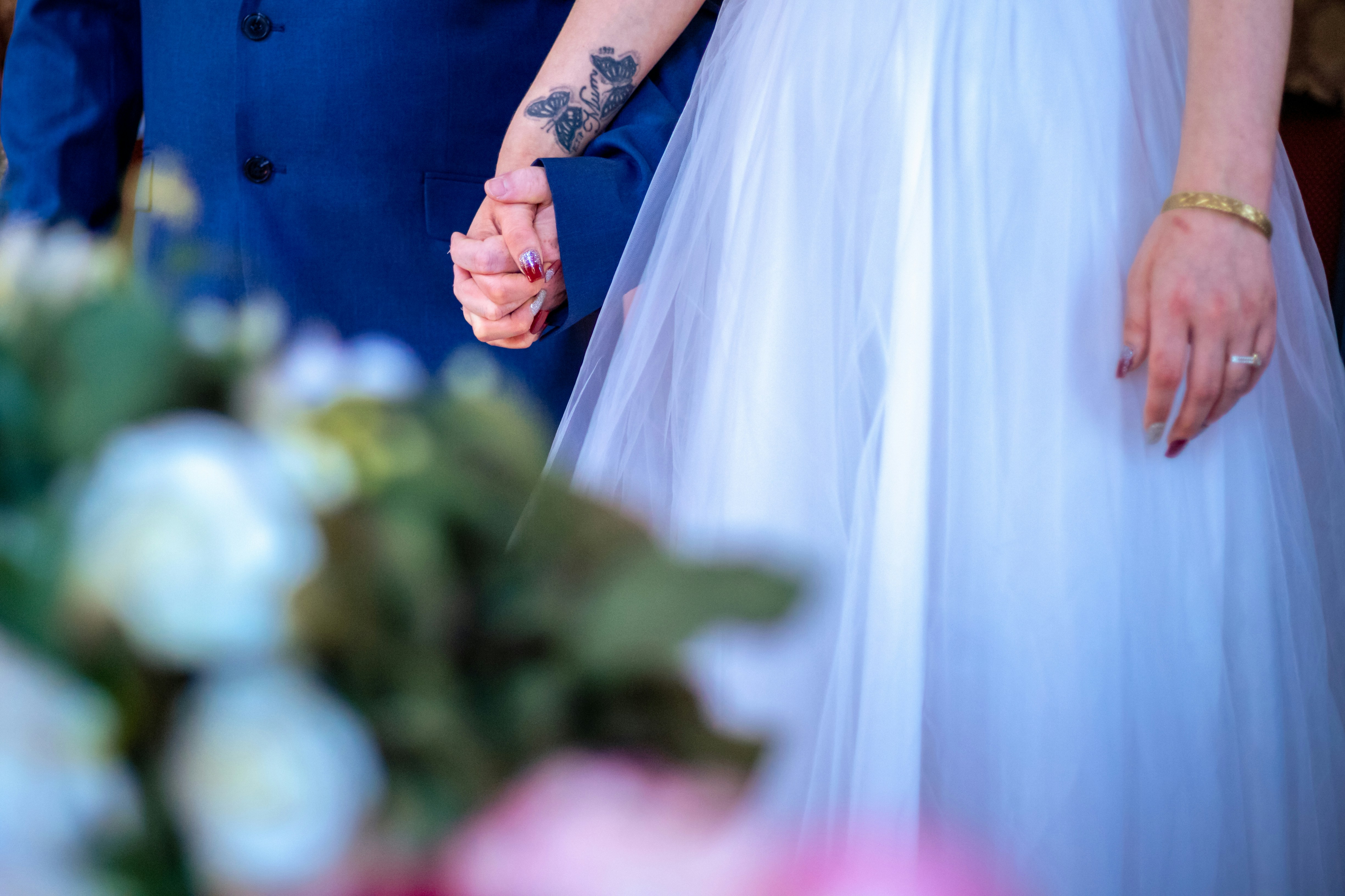A bride and groom holding hands, standing in front of a vibrant floral arrangement, radiating love and joy. If you'd like to support me as a creator, please consider sending a donation via Paypal: https://www.paypal.com/donate/?hosted_button_id=XRK26QKQY9RGW
