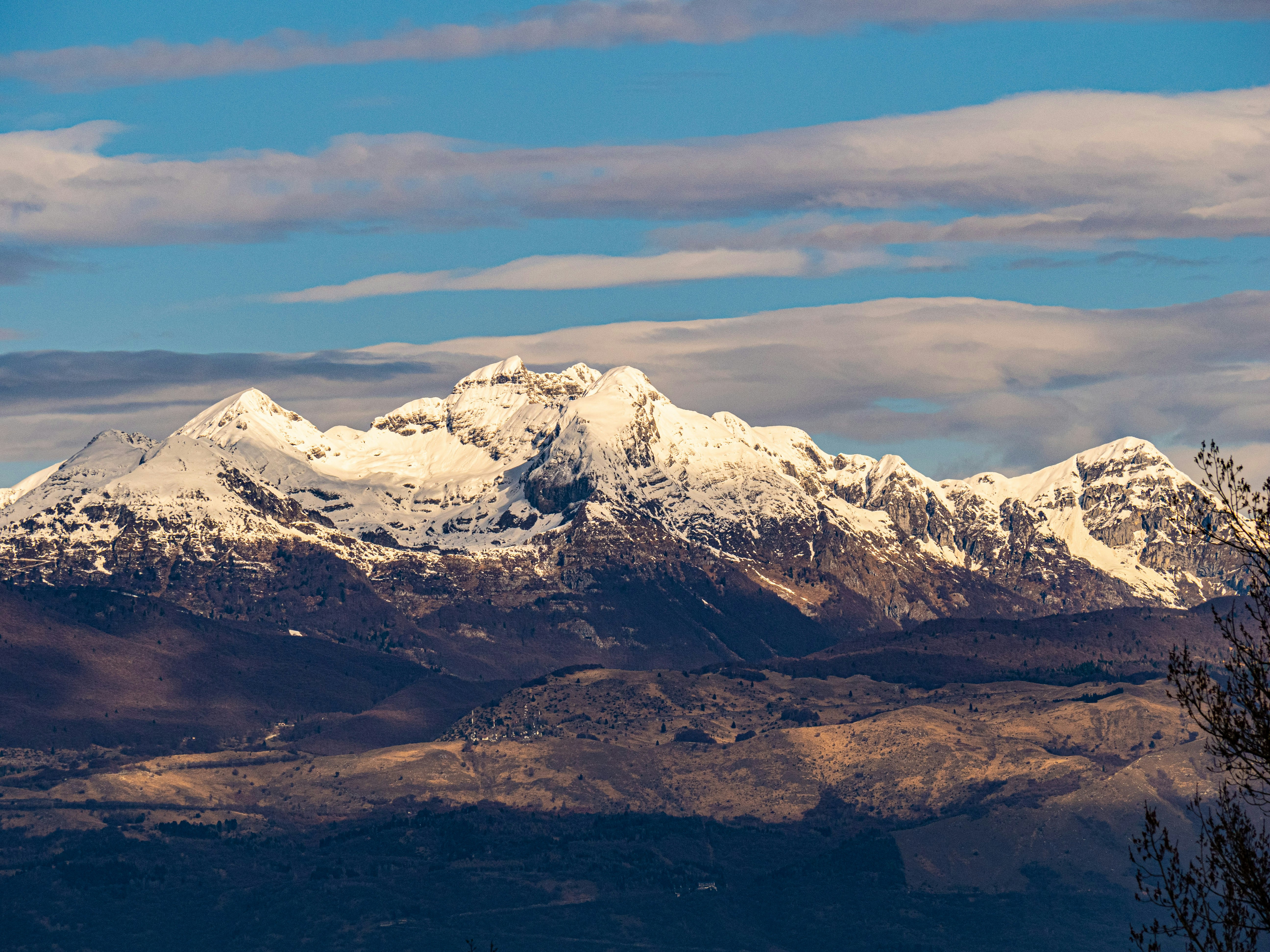 Majestic mountain range adorned with snow under a vibrant sky, showcasing the rugged beauty of nature.
