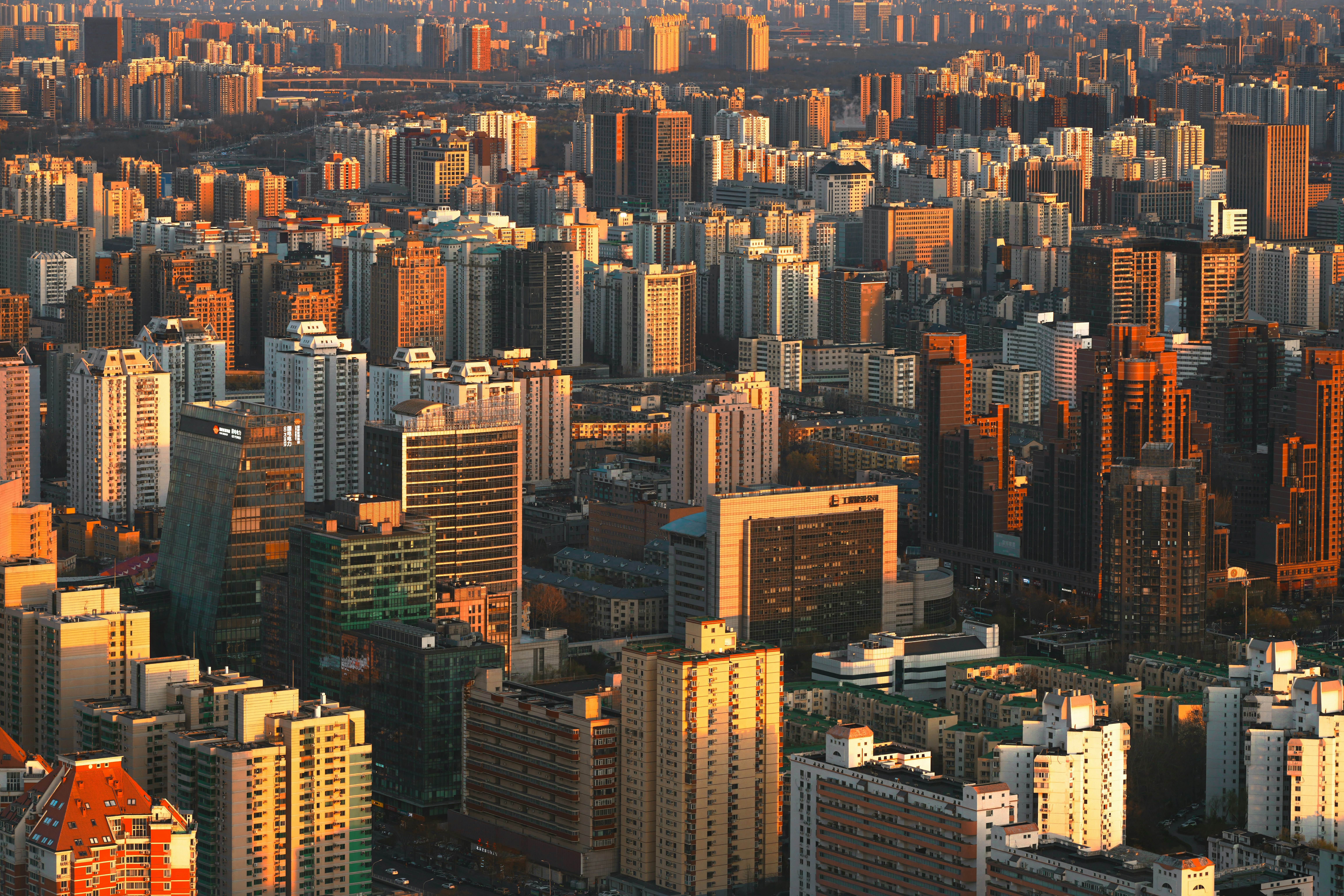 Dense cityscape with high-rise buildings illuminated by warm sunset light.