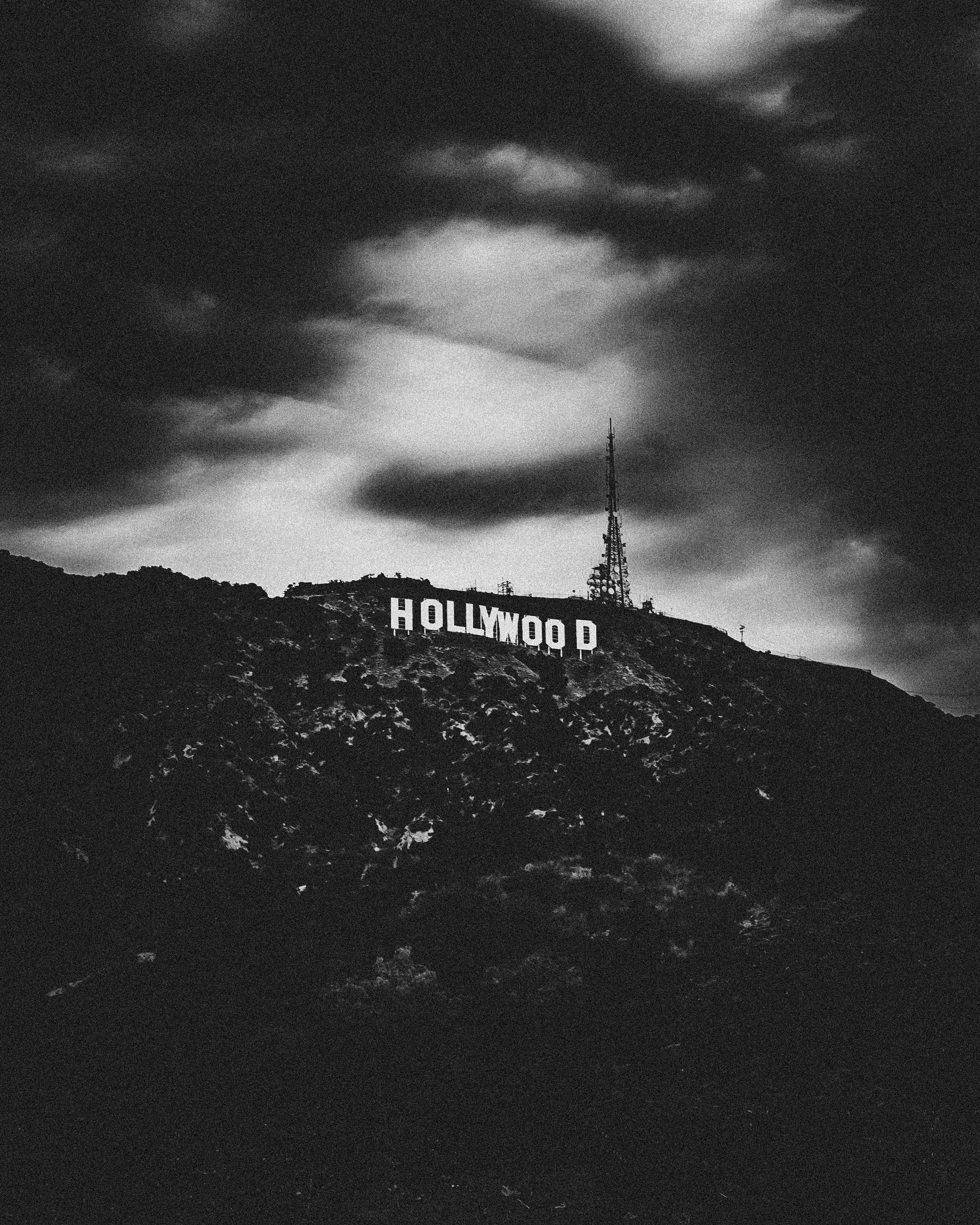 Black and white view of the Hollywood sign under a dramatic sky.