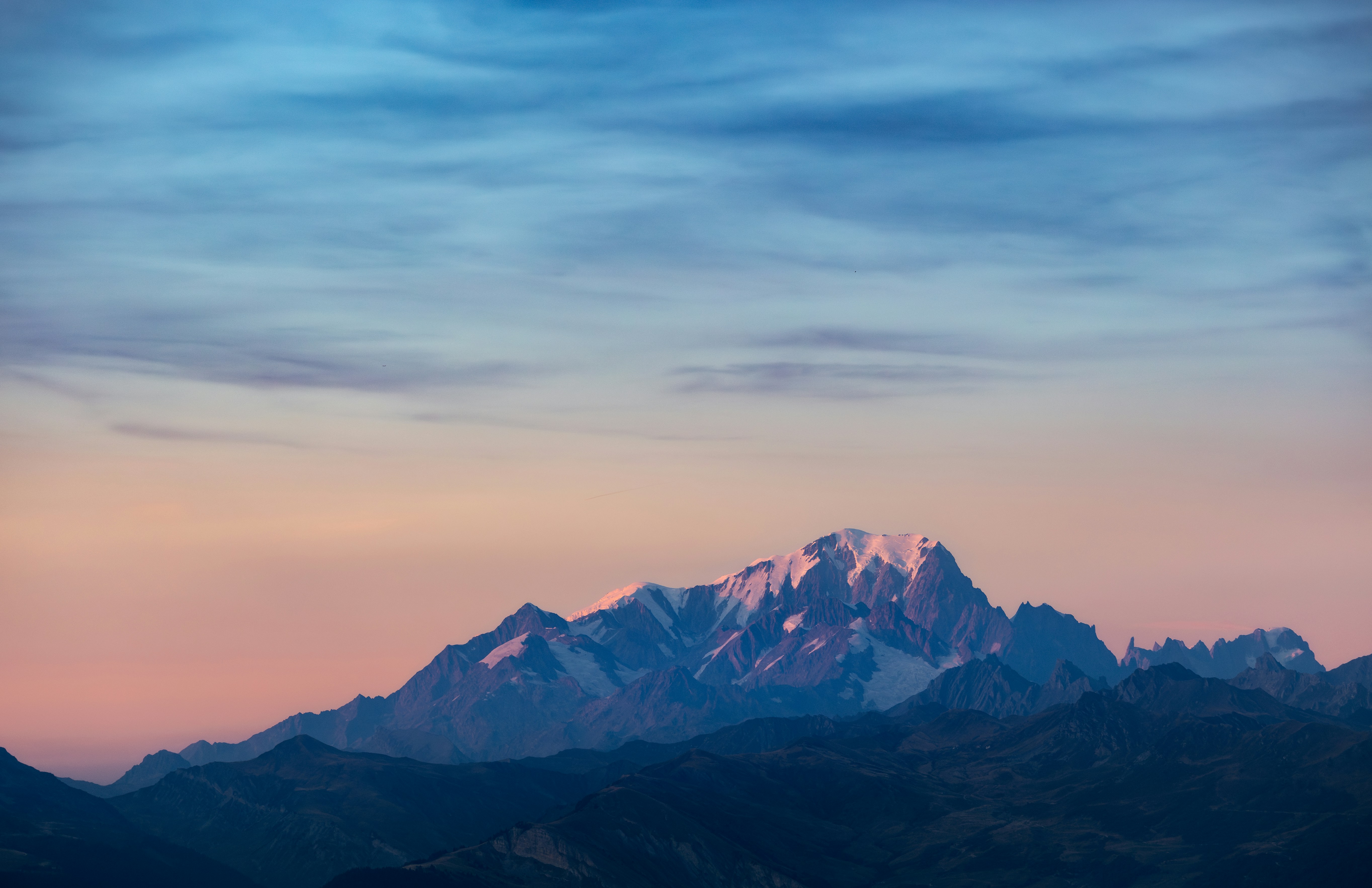 Snow-capped mountain under a pastel sky at dusk.