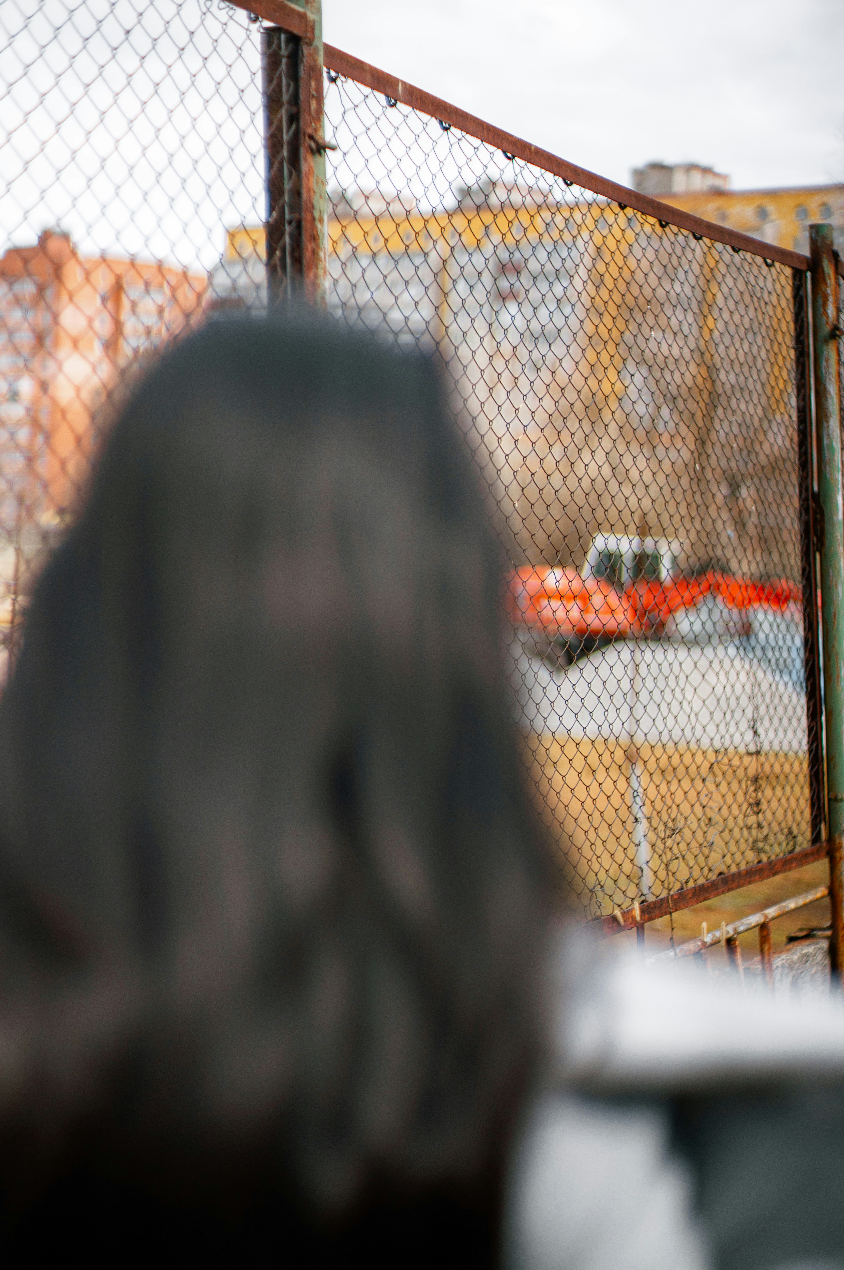 A person looks through a rusty chain link fence. photo – Free Woman ...