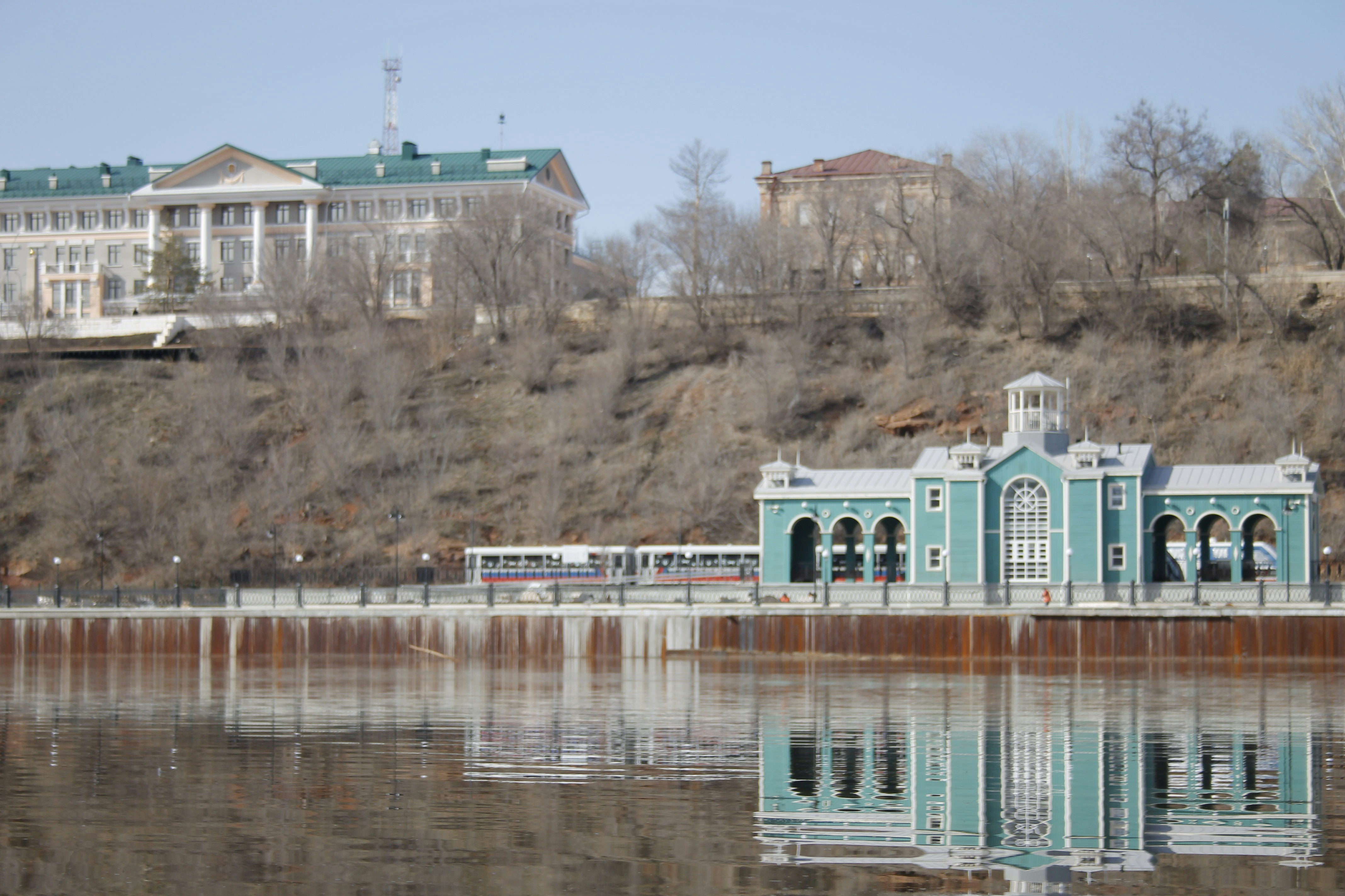 Buildings stand reflected in calm water.