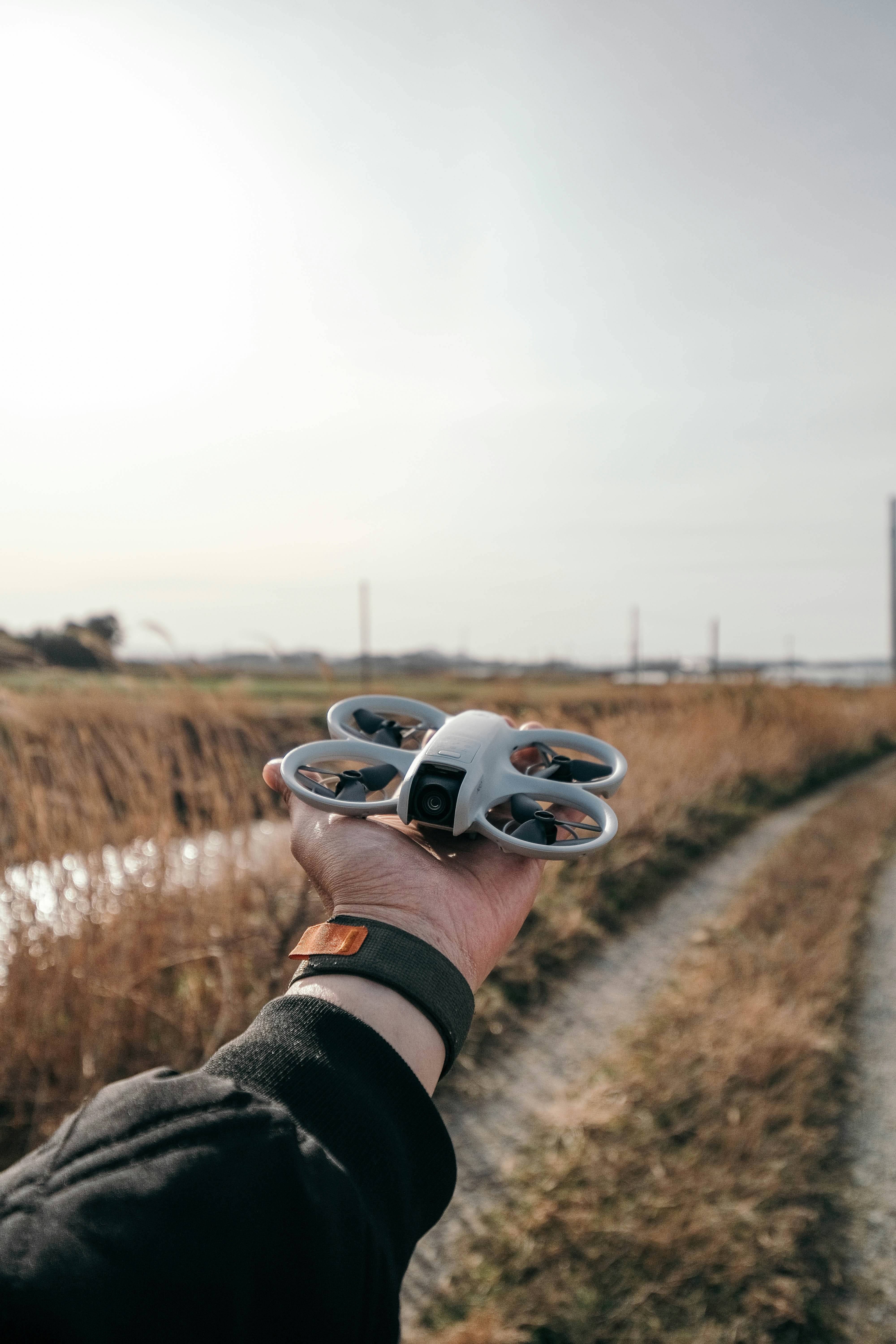 Grip and Glide: A handheld quadcopter poised along a sunlit country path