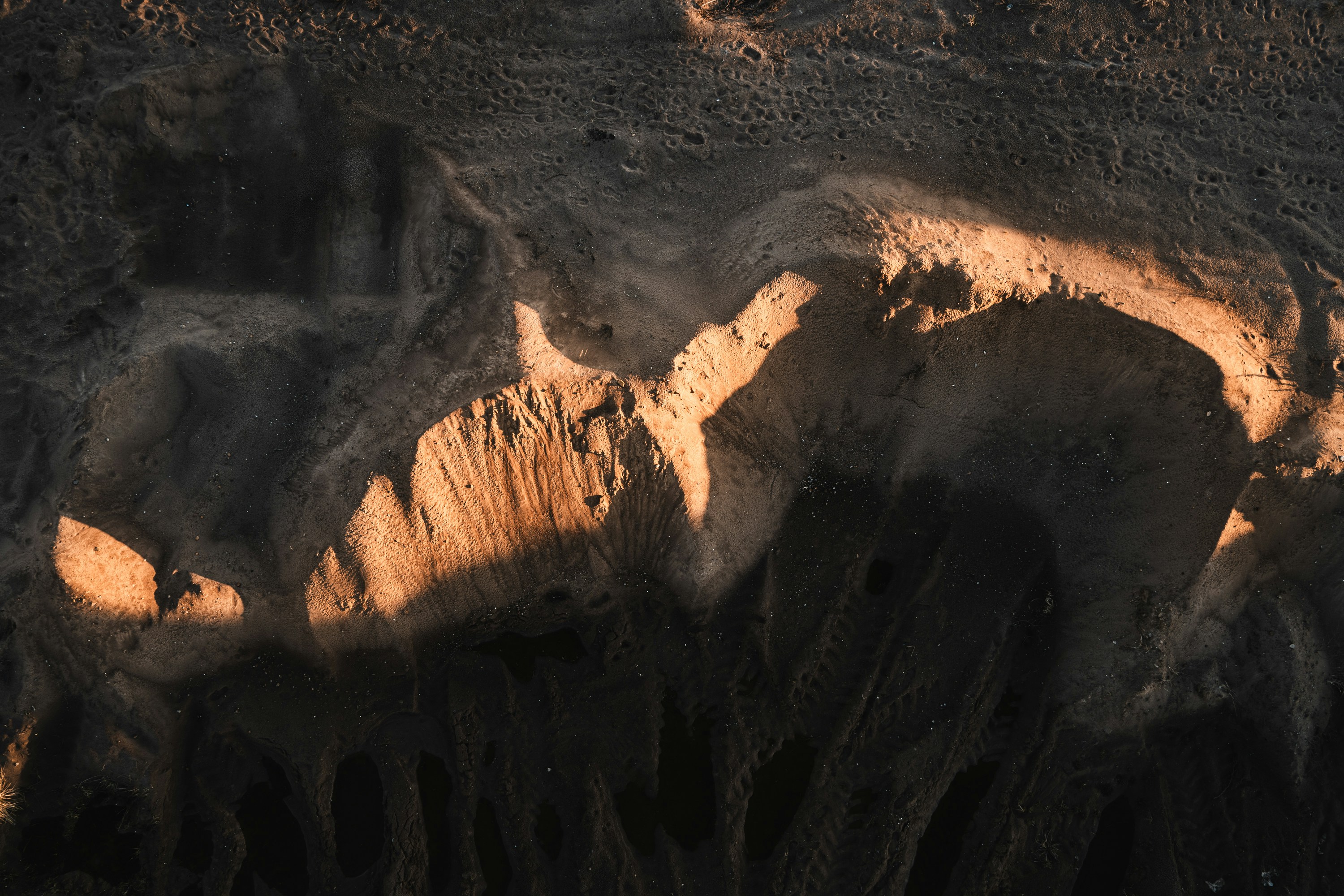 Sunlight casts dramatic shadows over a rugged canyon landscape.