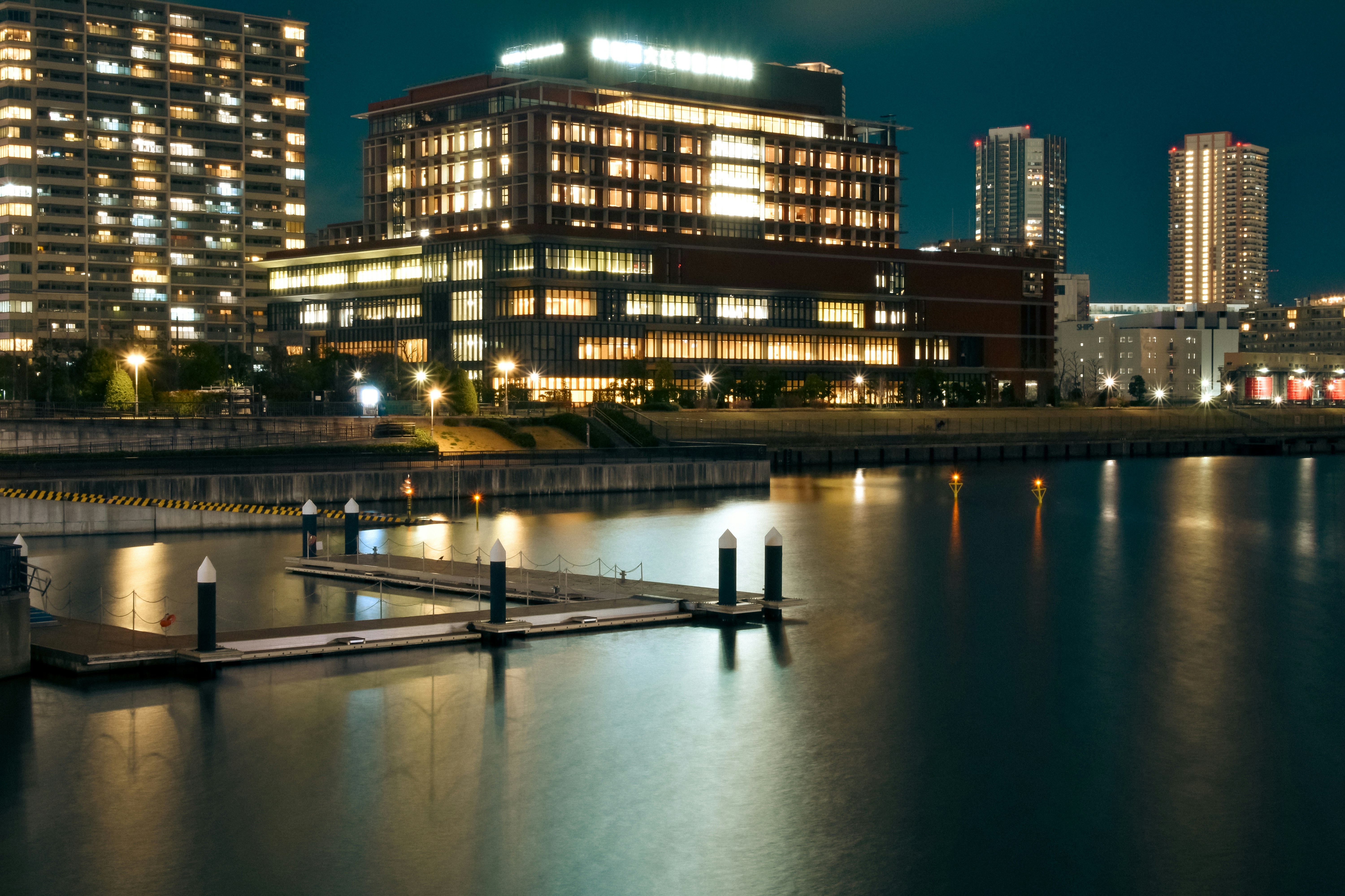City buildings light up by a still waterfront at night. photo – Free ...
