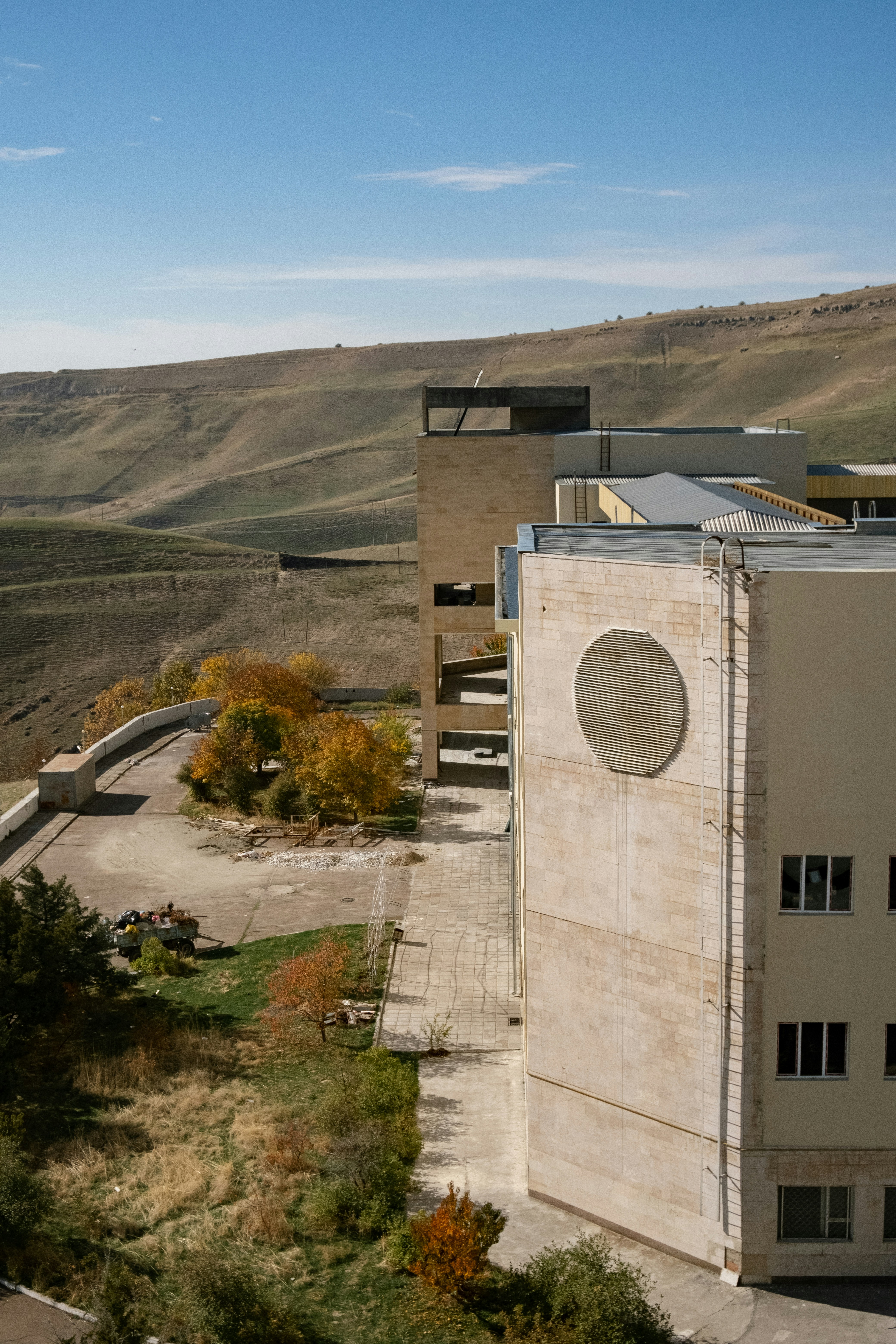 Circular Vent on a Sunlit Campus Wall: A Quiet Hillside Prospect