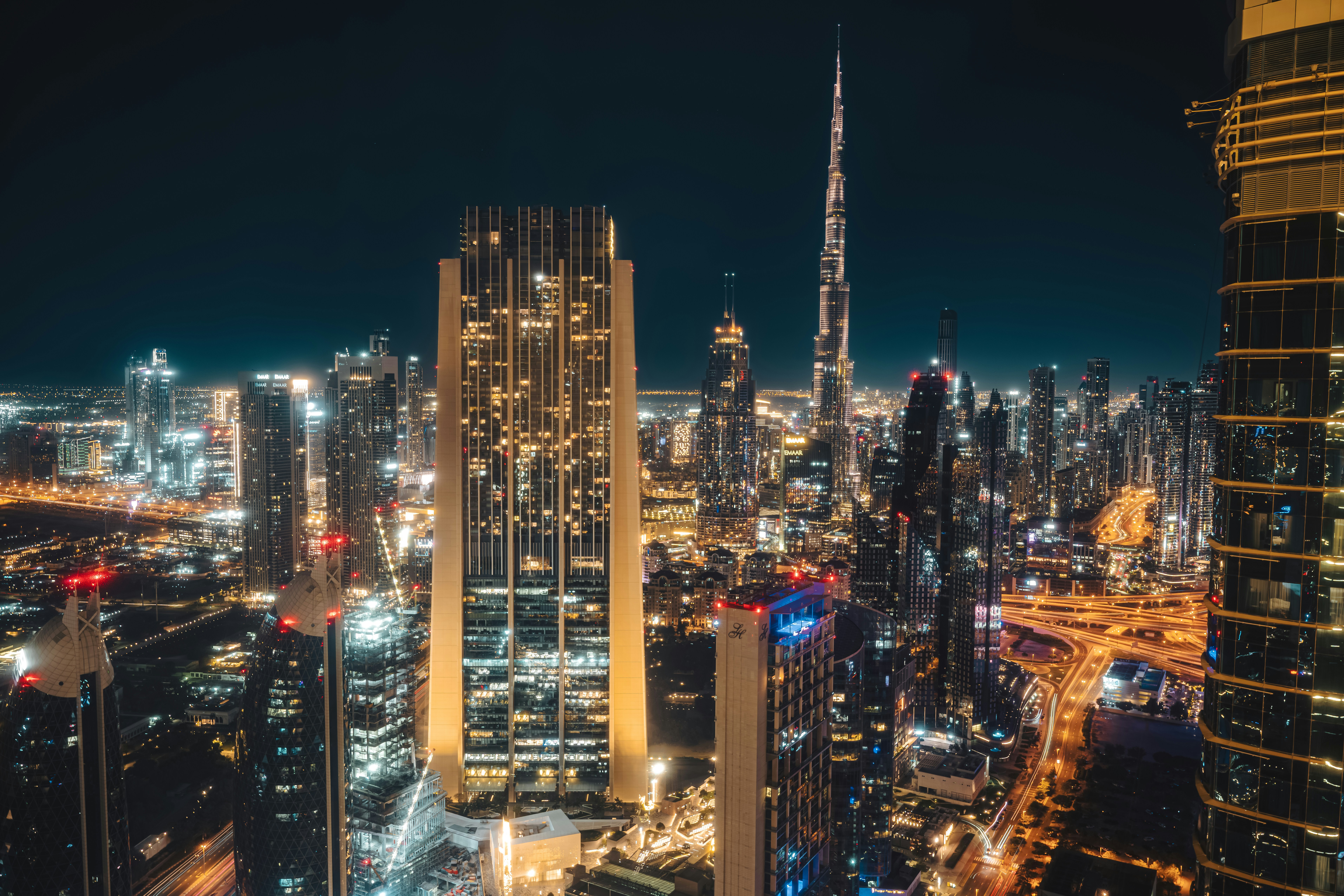 Vibrant city skyline illuminated at night, with towering skyscrapers and bustling streets below.