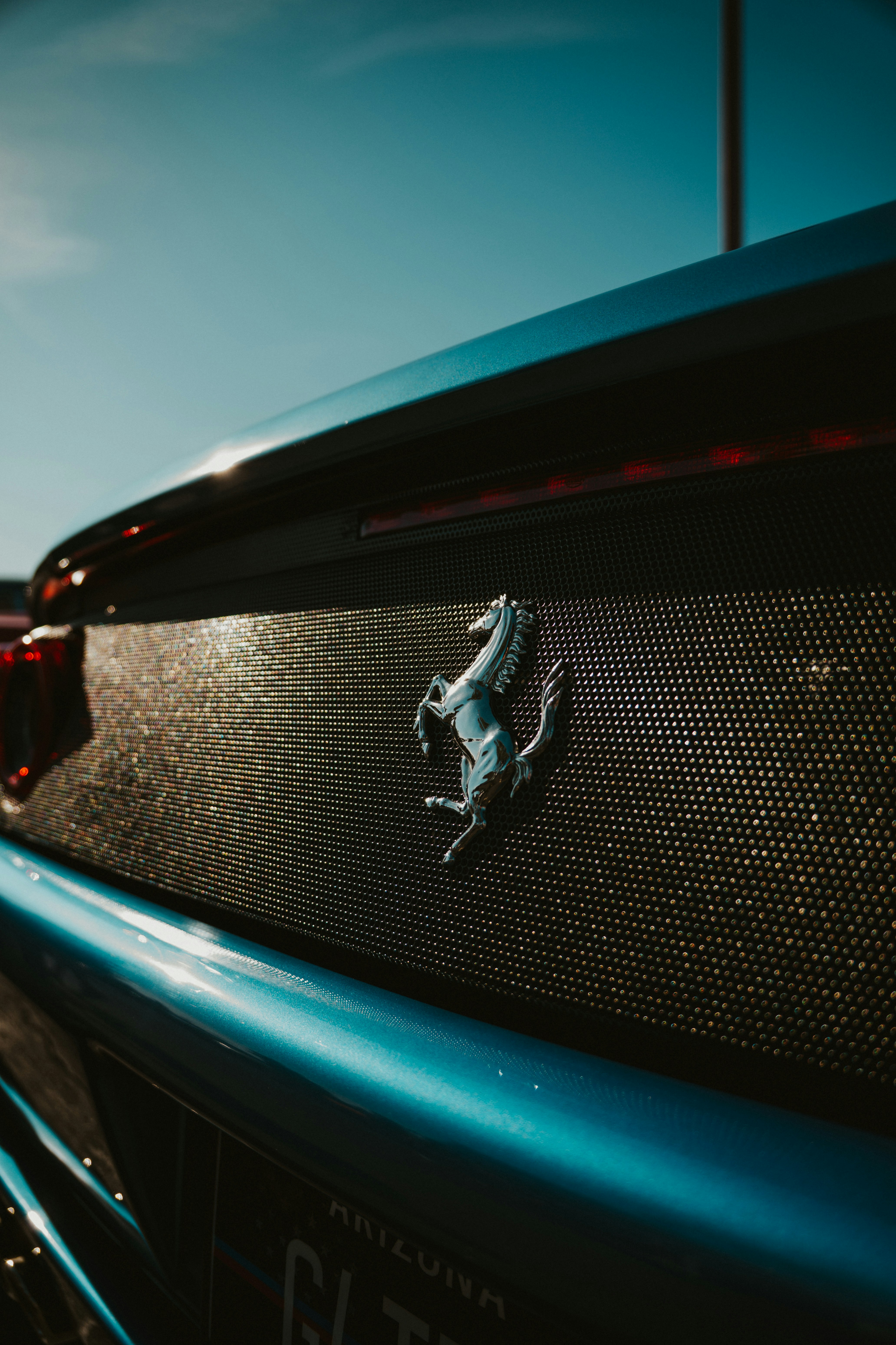 Emblem in cobalt glare: a close-up of Ferrari's badge on perforated blue grille