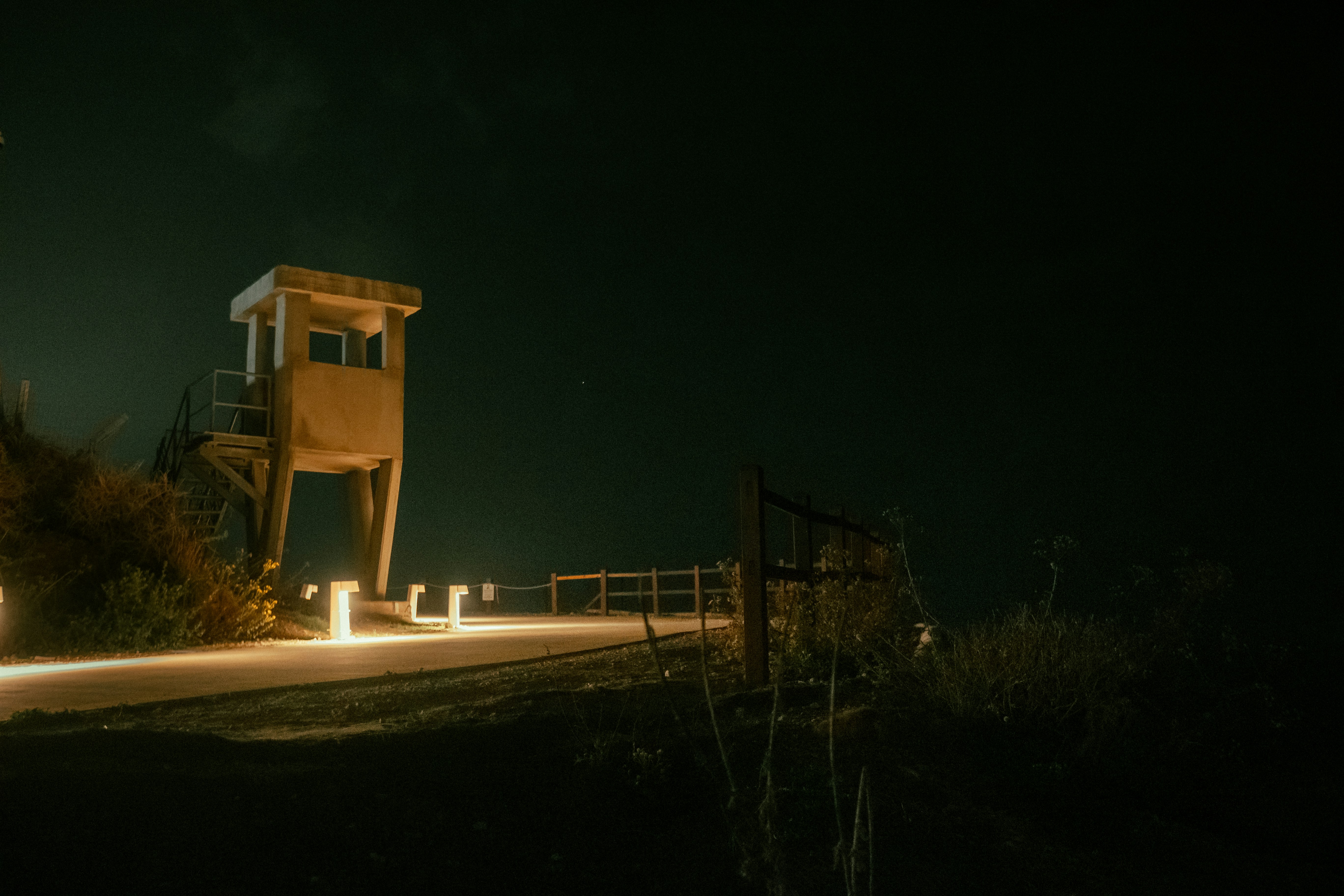 Watchtower illuminated by soft light against a dark, starry night.