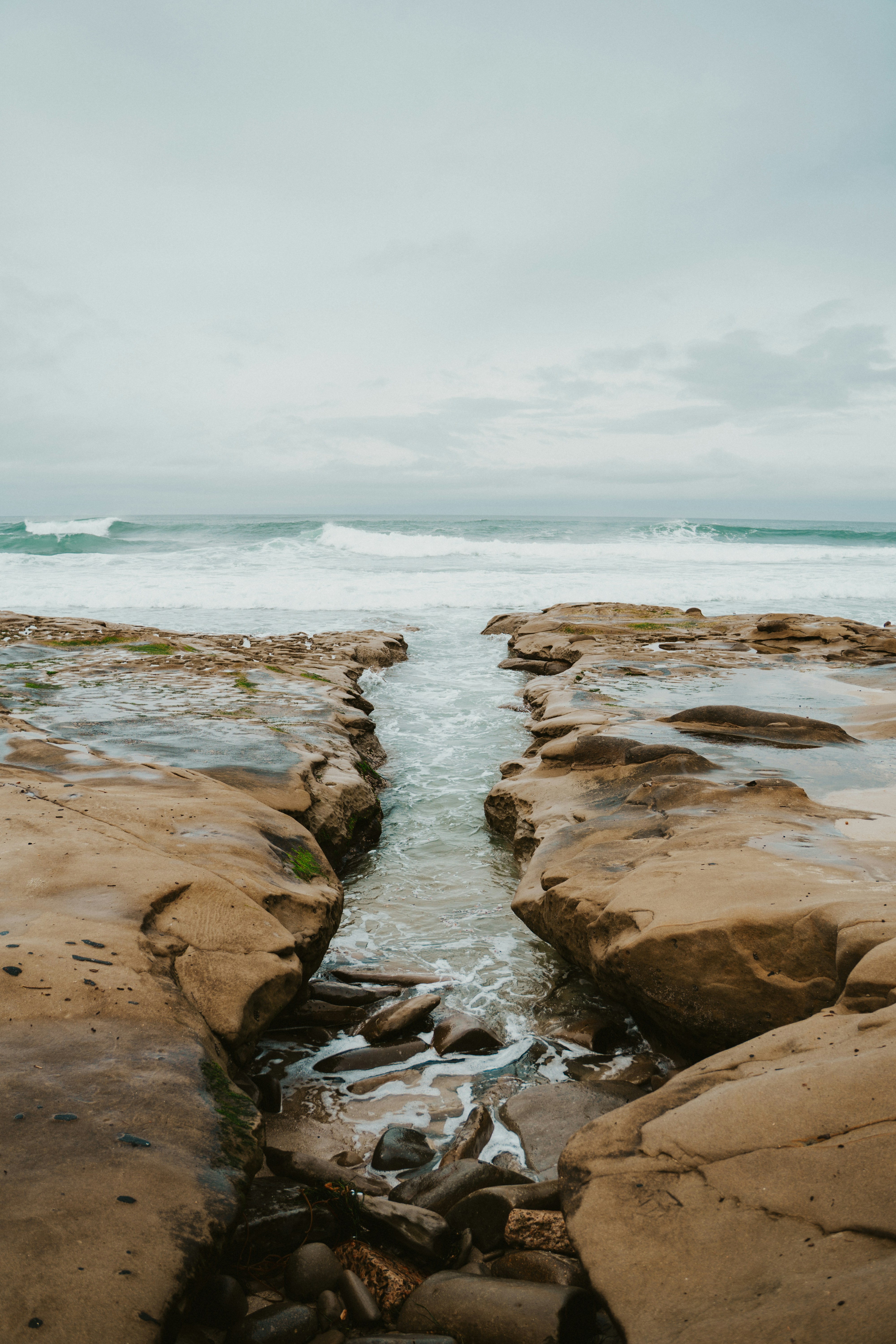 Water flows through rocks toward the ocean.