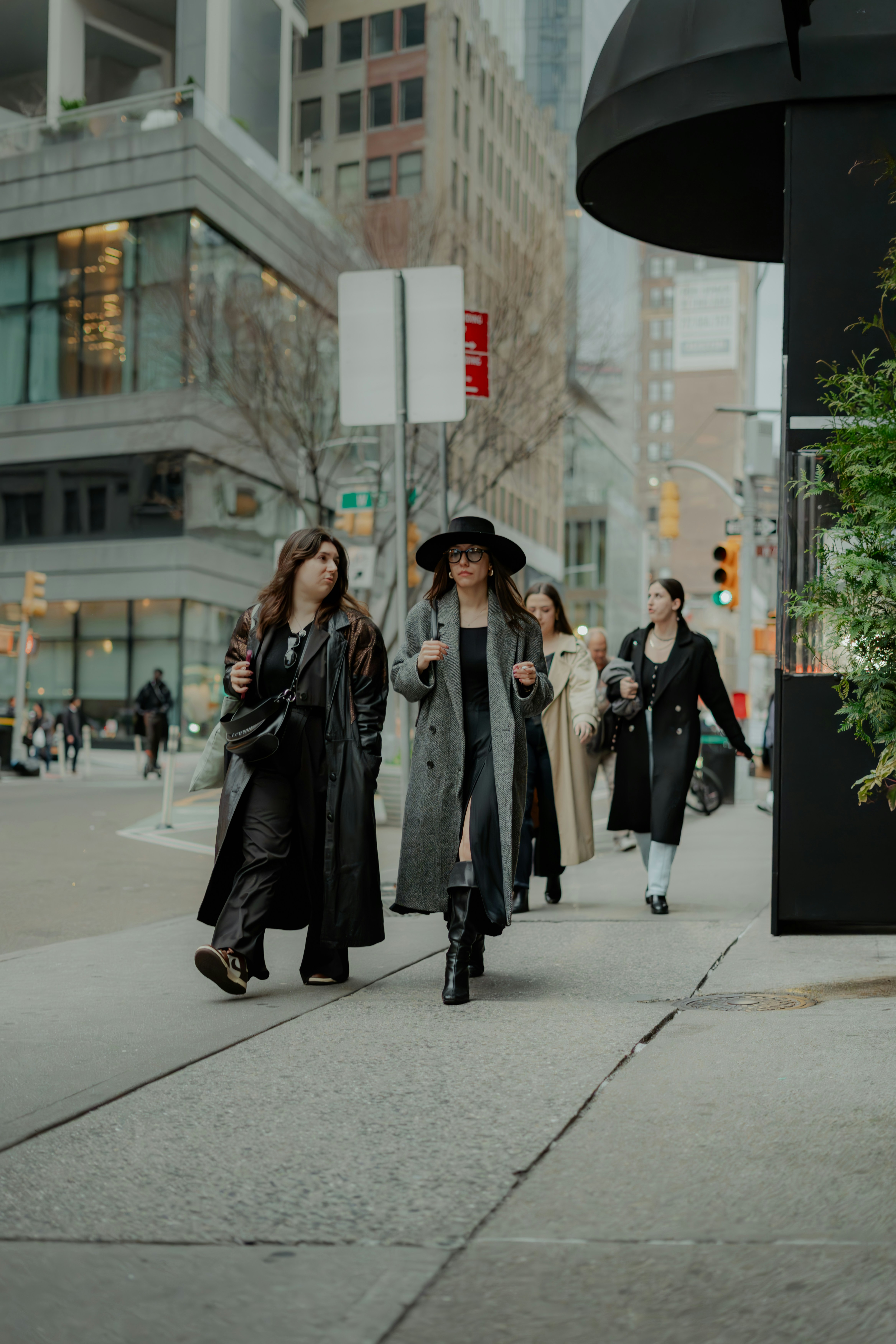 Group of stylish individuals walking along a city street, surrounded by modern architecture.