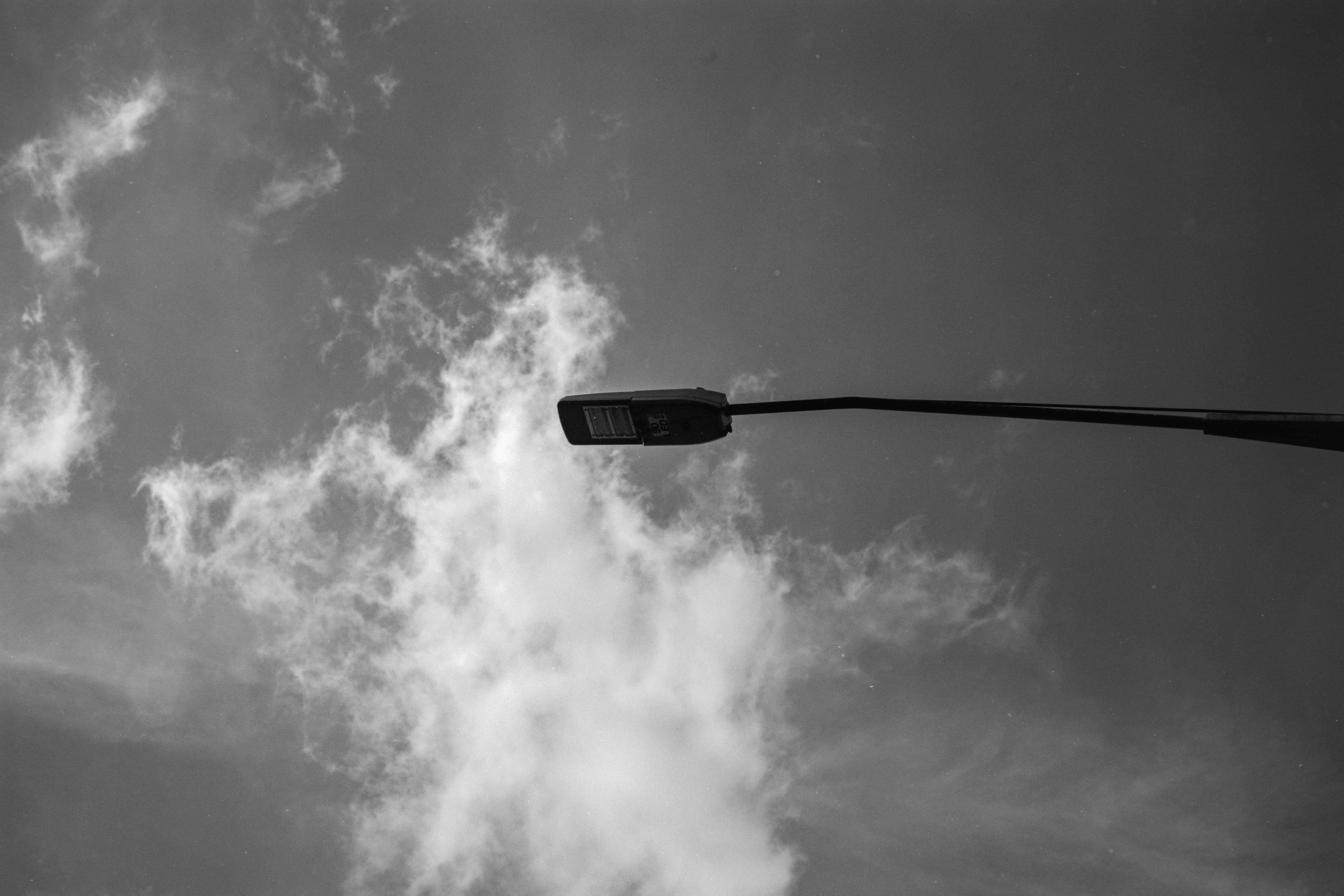 Street lamp silhouetted against a dramatic cloud-filled sky in monochrome.