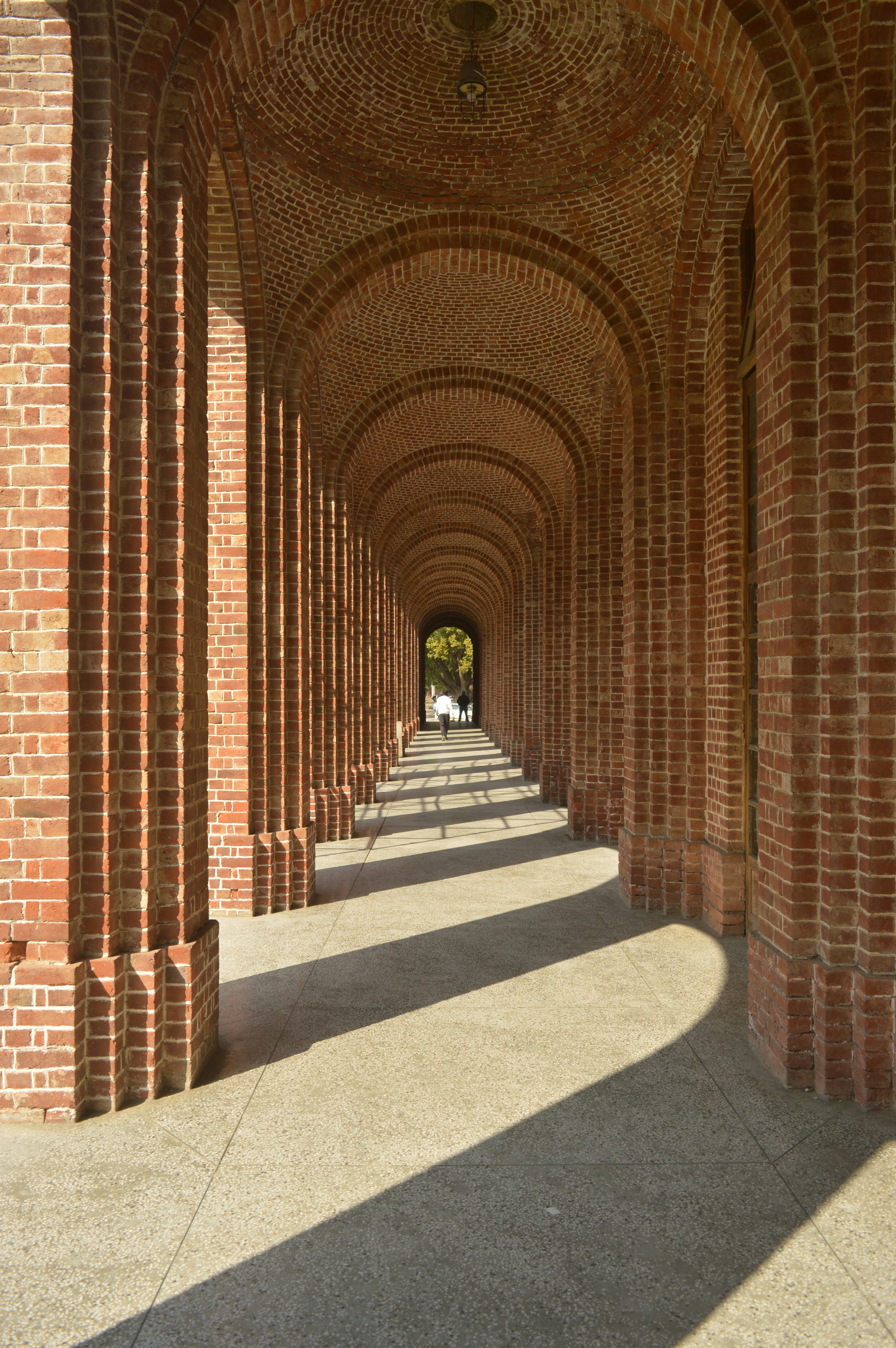 A brick-walled archway extends into the distance. photo – Free Building ...