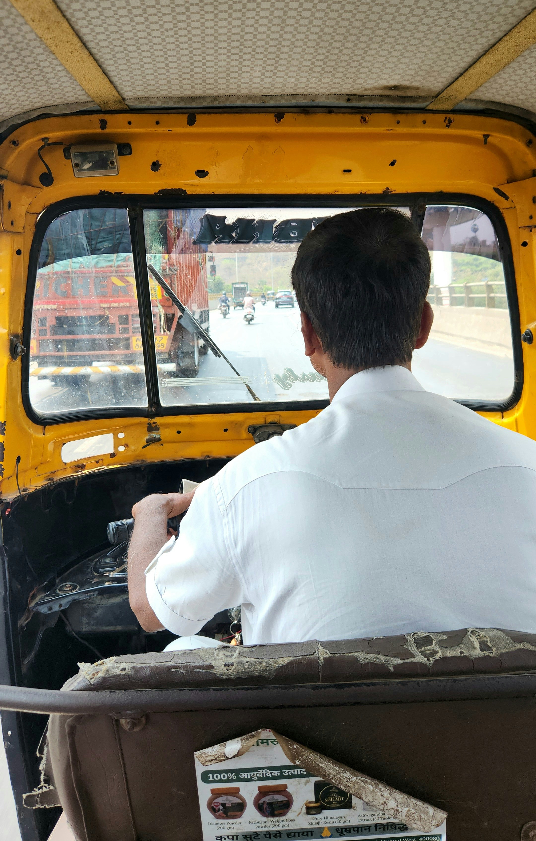 Behind the Wheel in Yellow: A Quiet Moment in a Busy Highway Tuk-Tuk